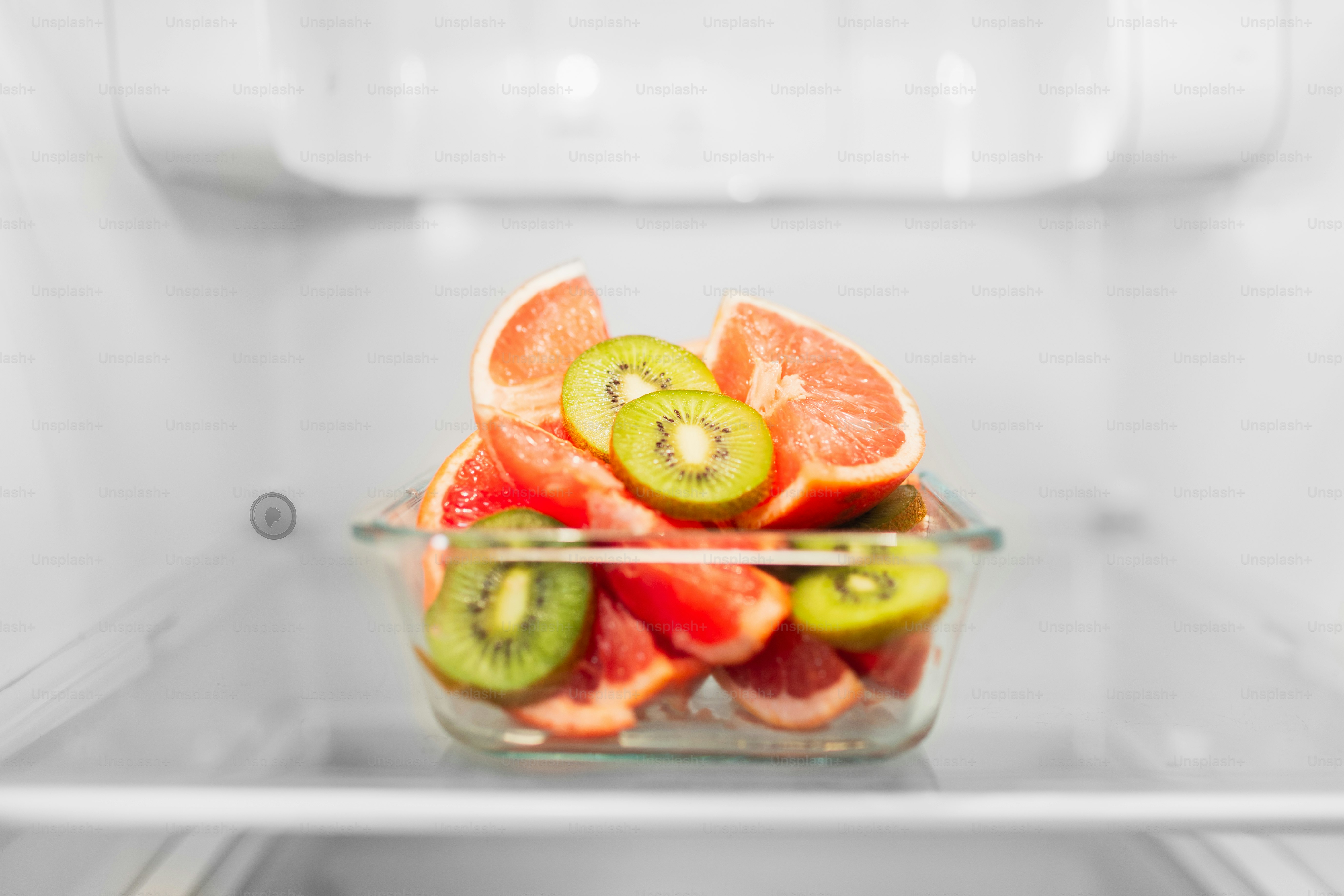 A bowl of sliced fruit inside of an open refrigerator photo – Fruits ...