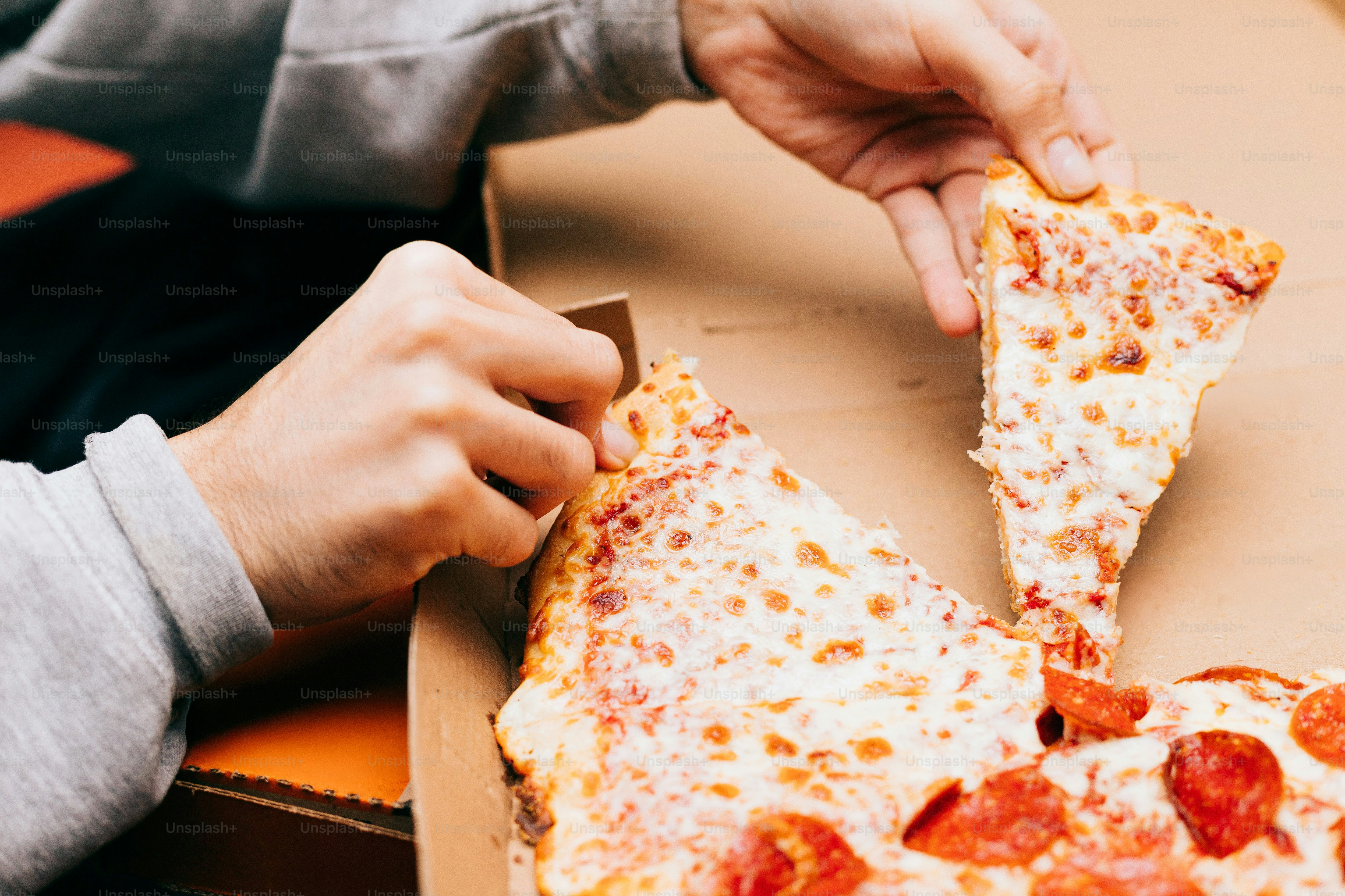 A person taking a slice of pizza from a box photo – Takeout food Image ...