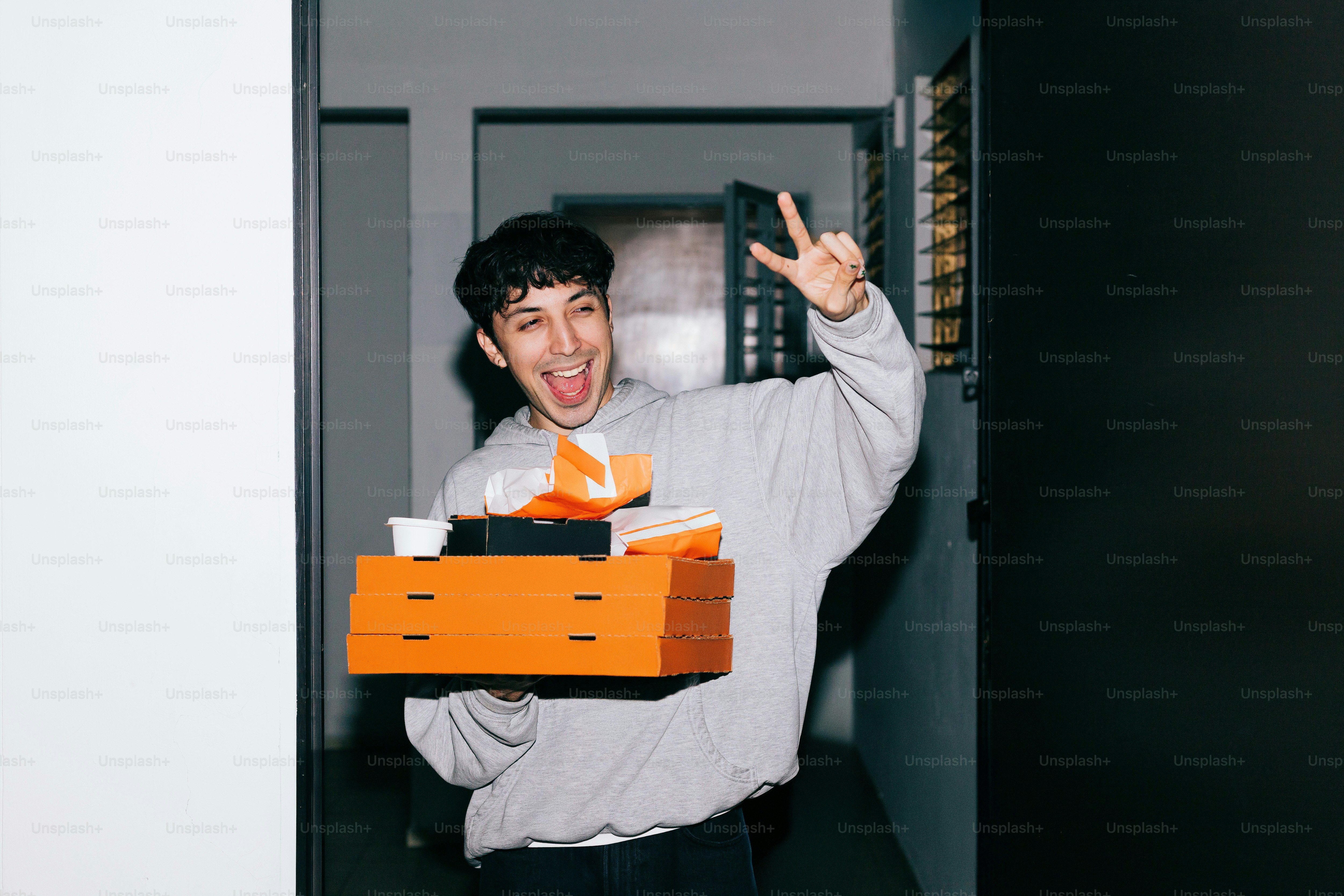 A man holding a box and making a peace sign photo – Takeout food Image ...