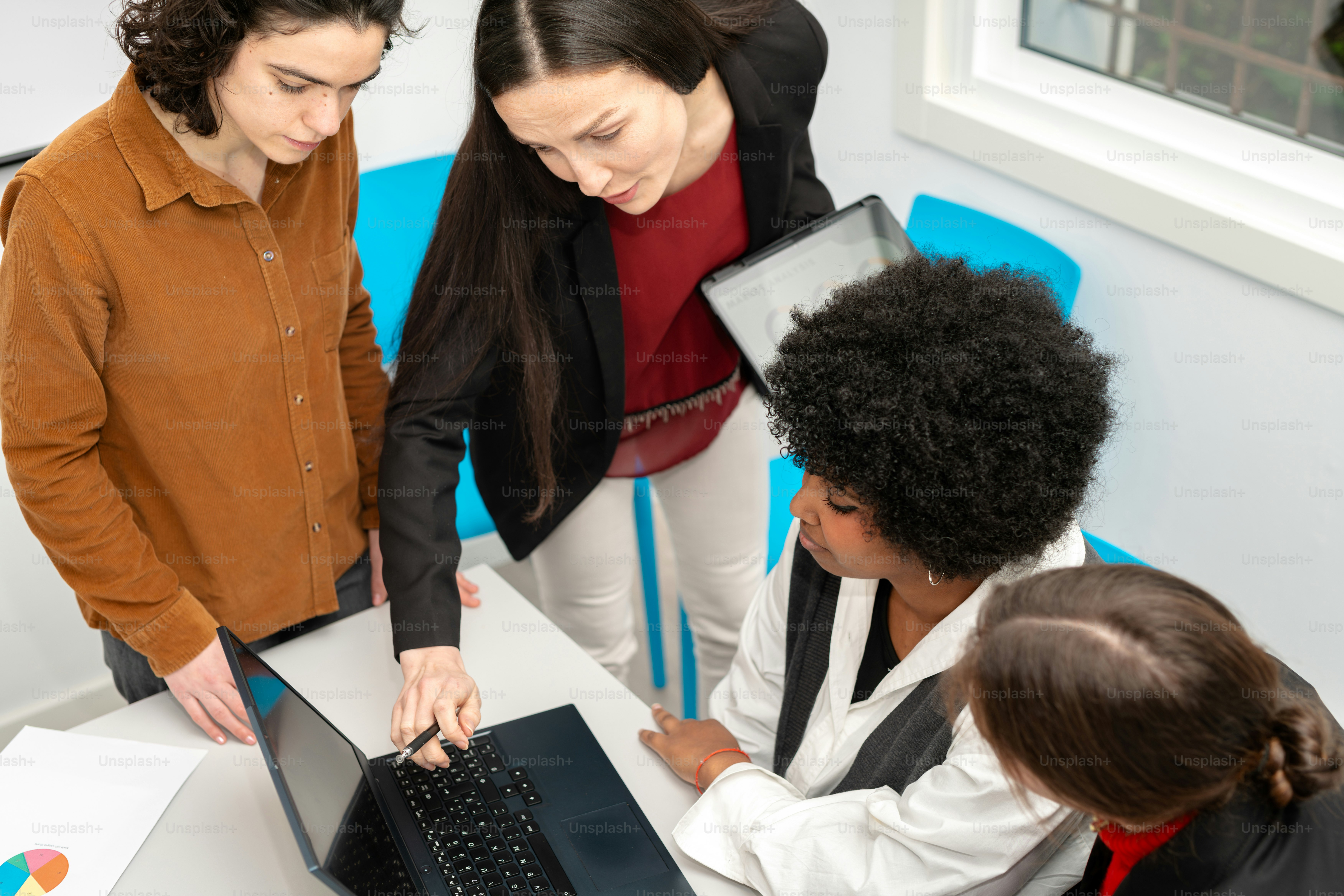 A group of women standing around a laptop computer photo – Colleagues ...