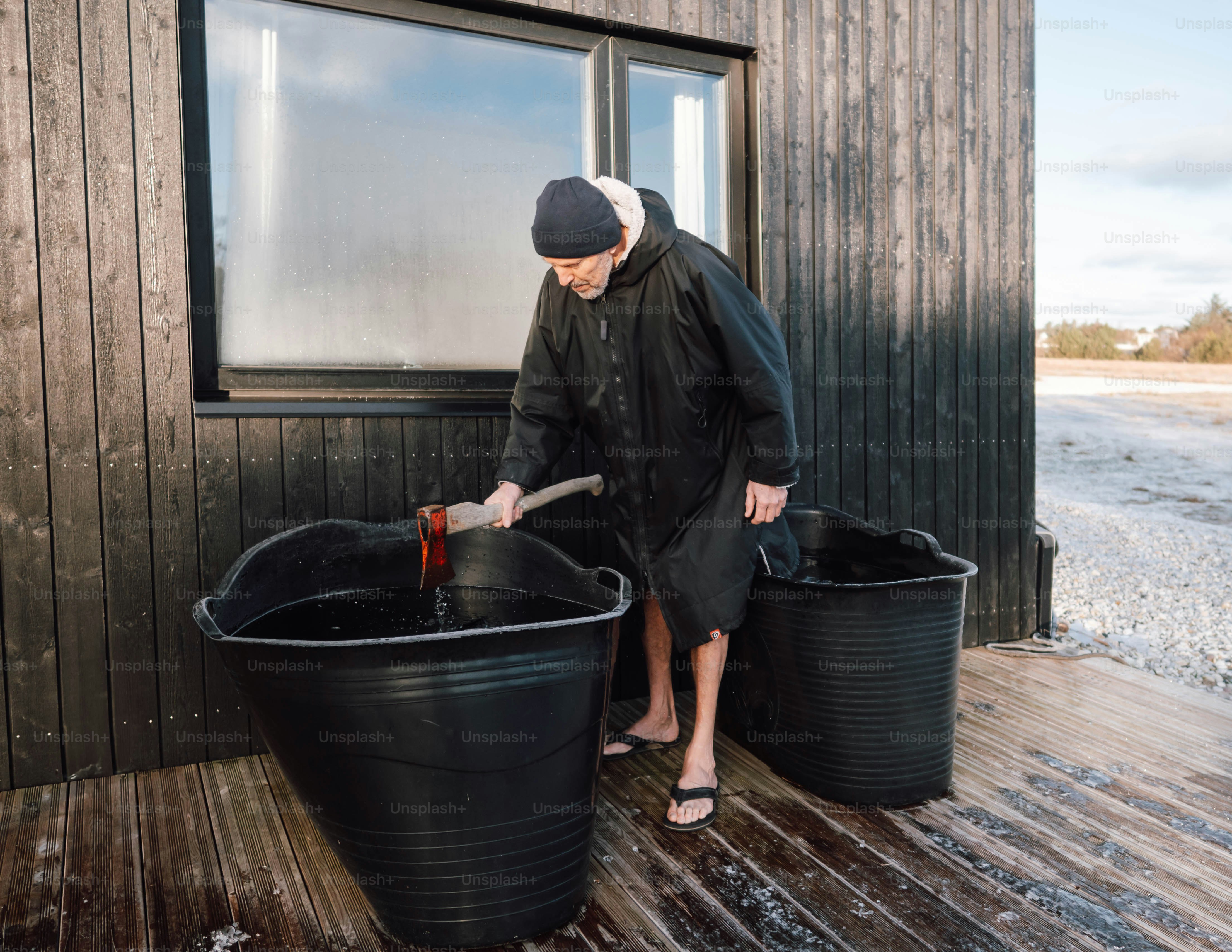 A man standing next to two buckets filled with water photo – Winter ...