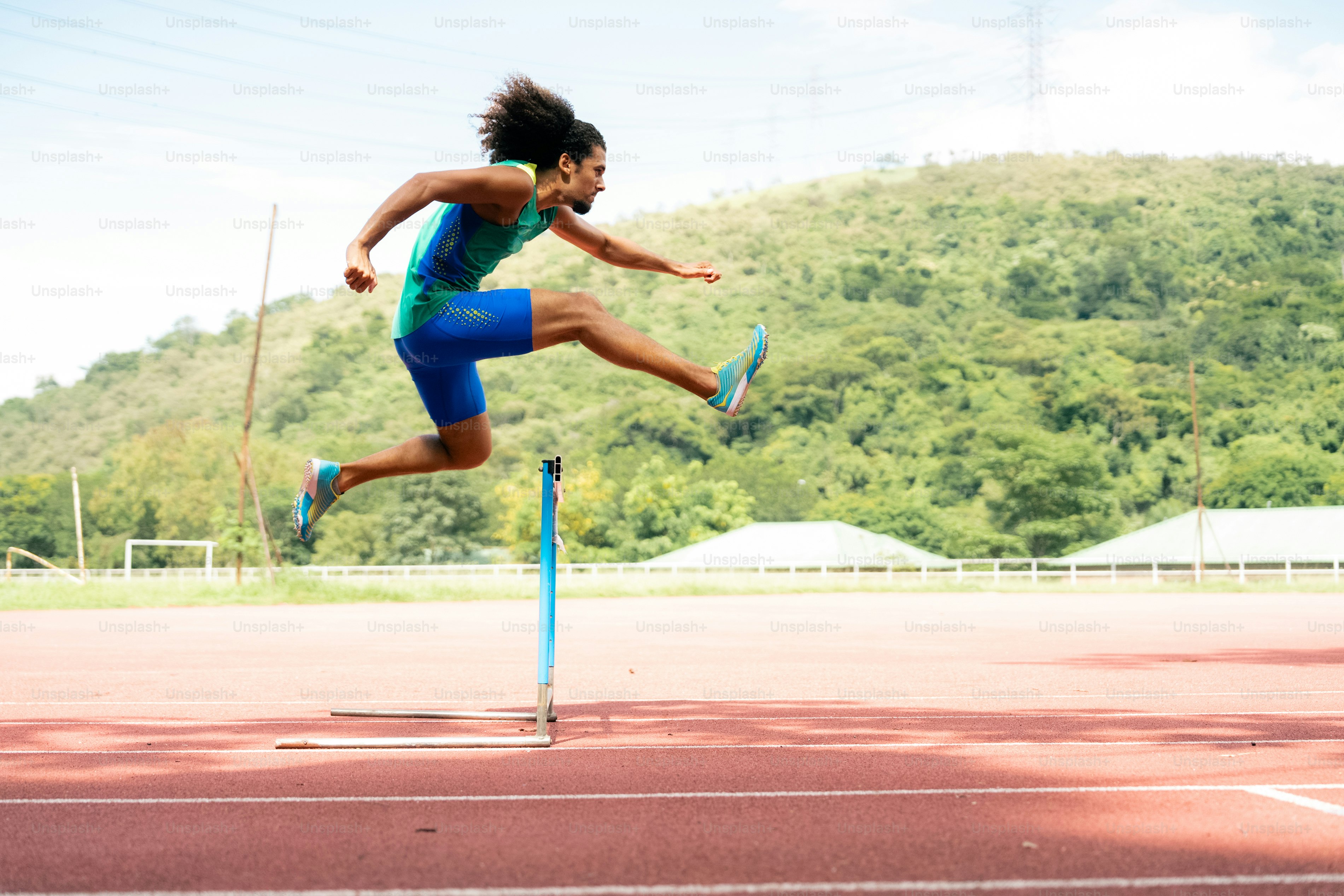 A woman is jumping over a hurdle on a track photo – Running Image on ...