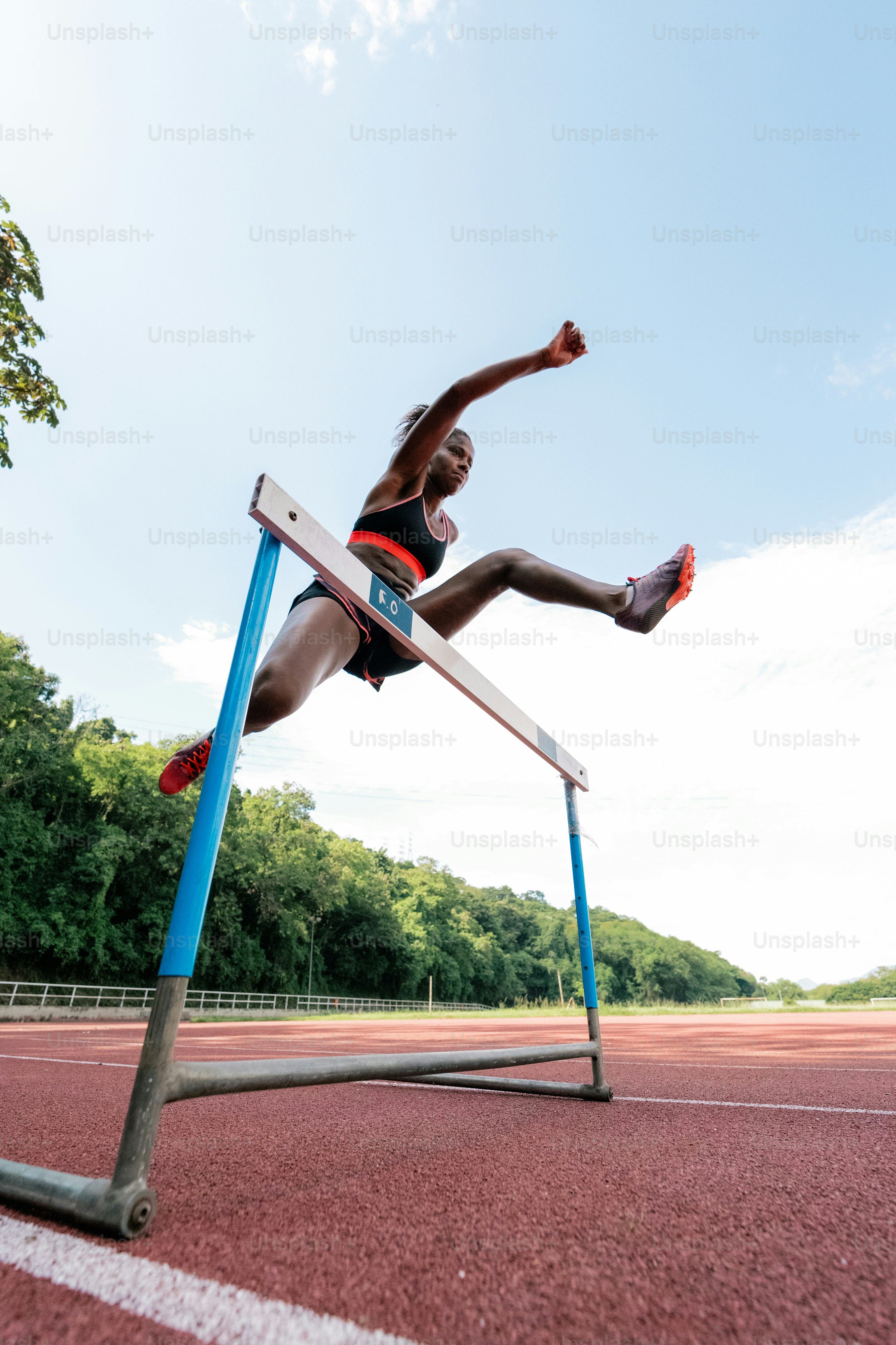 A person jumping over a hurdle on a track photo – Hurdle jump Image on ...