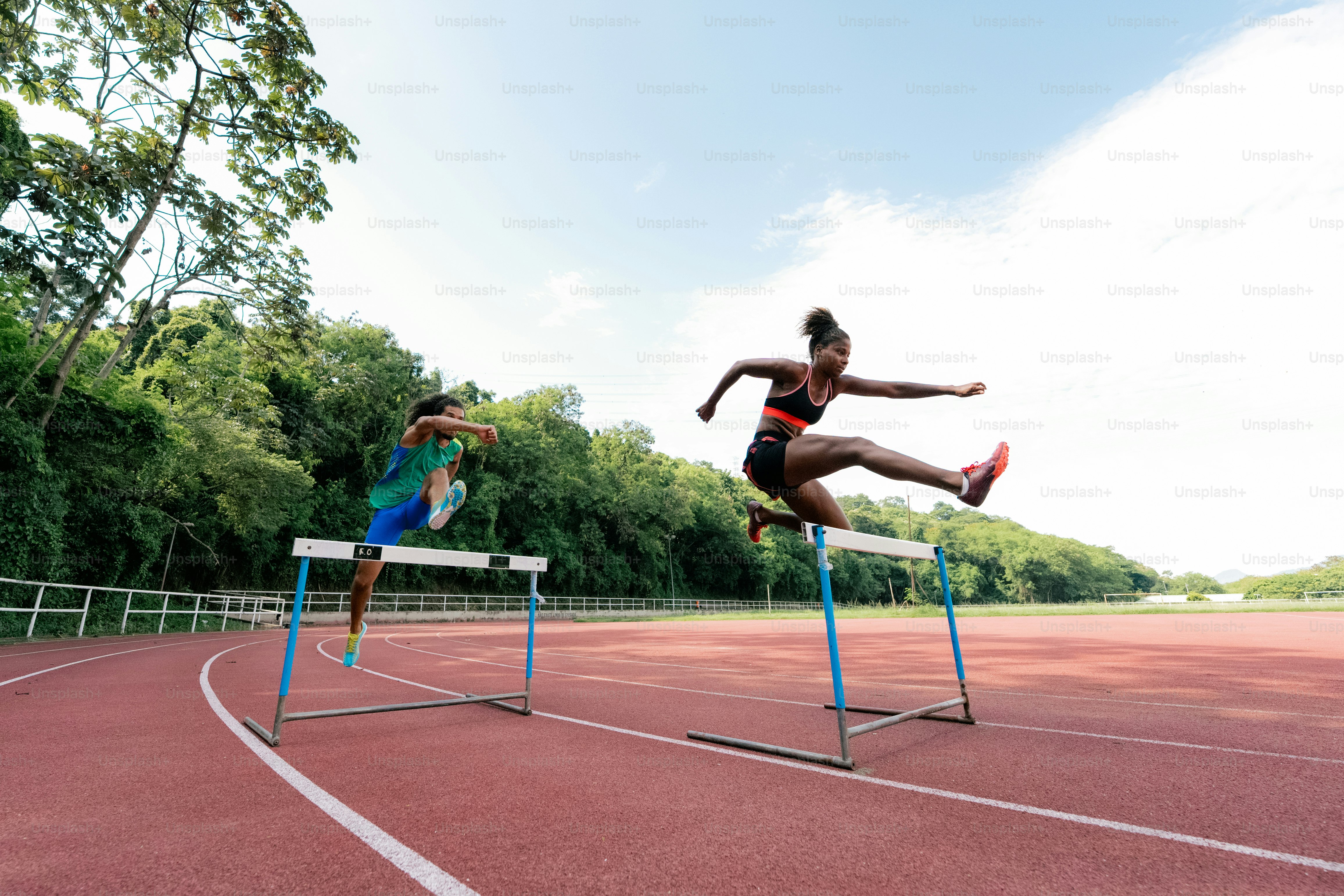 A person jumping over a hurdle on a track photo – Hurdle jump Image on ...