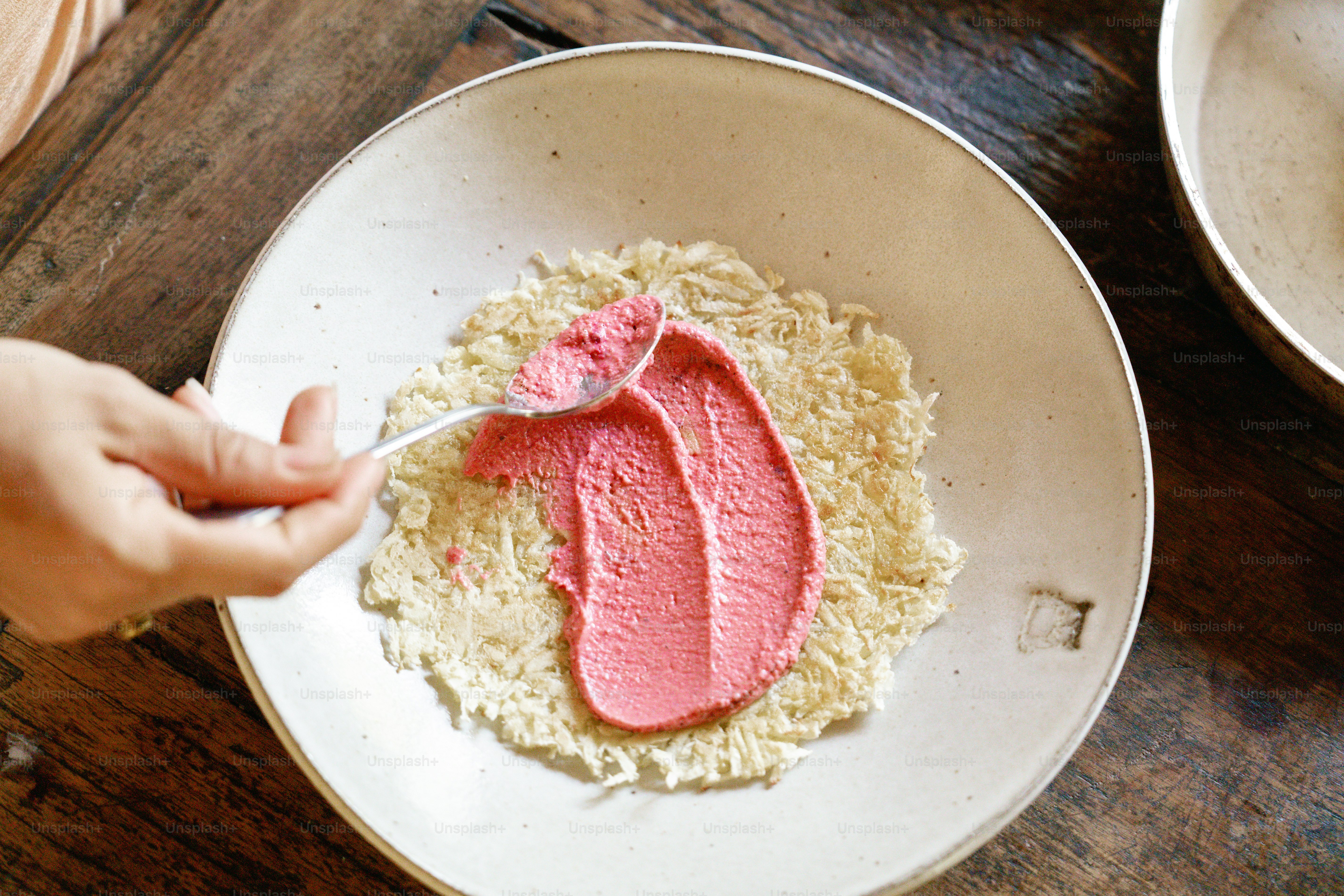 A person is decorating a cake with pink icing photo – Food Image on ...