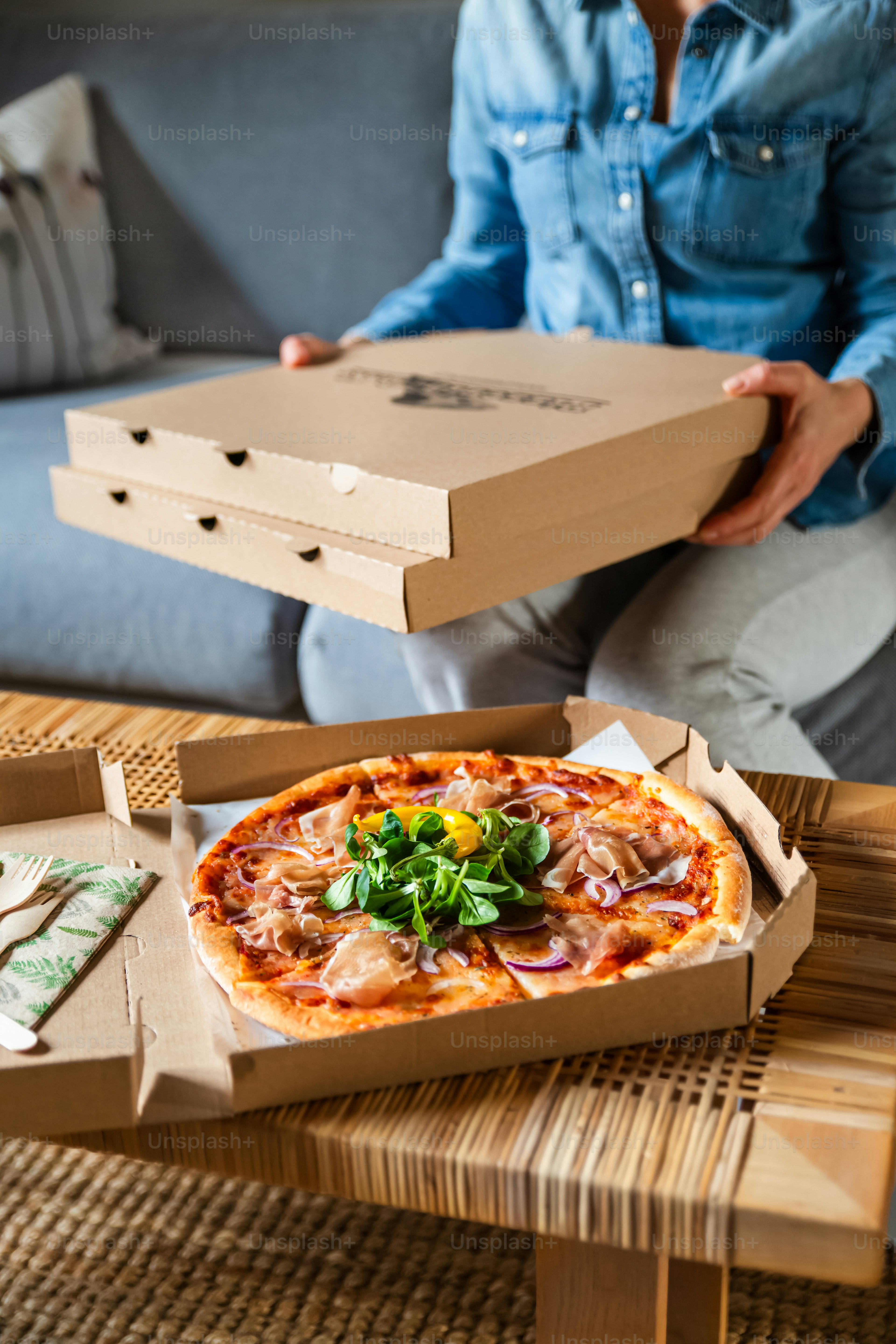 A person sitting on a couch with a pizza in a box photo – Pizza Image ...