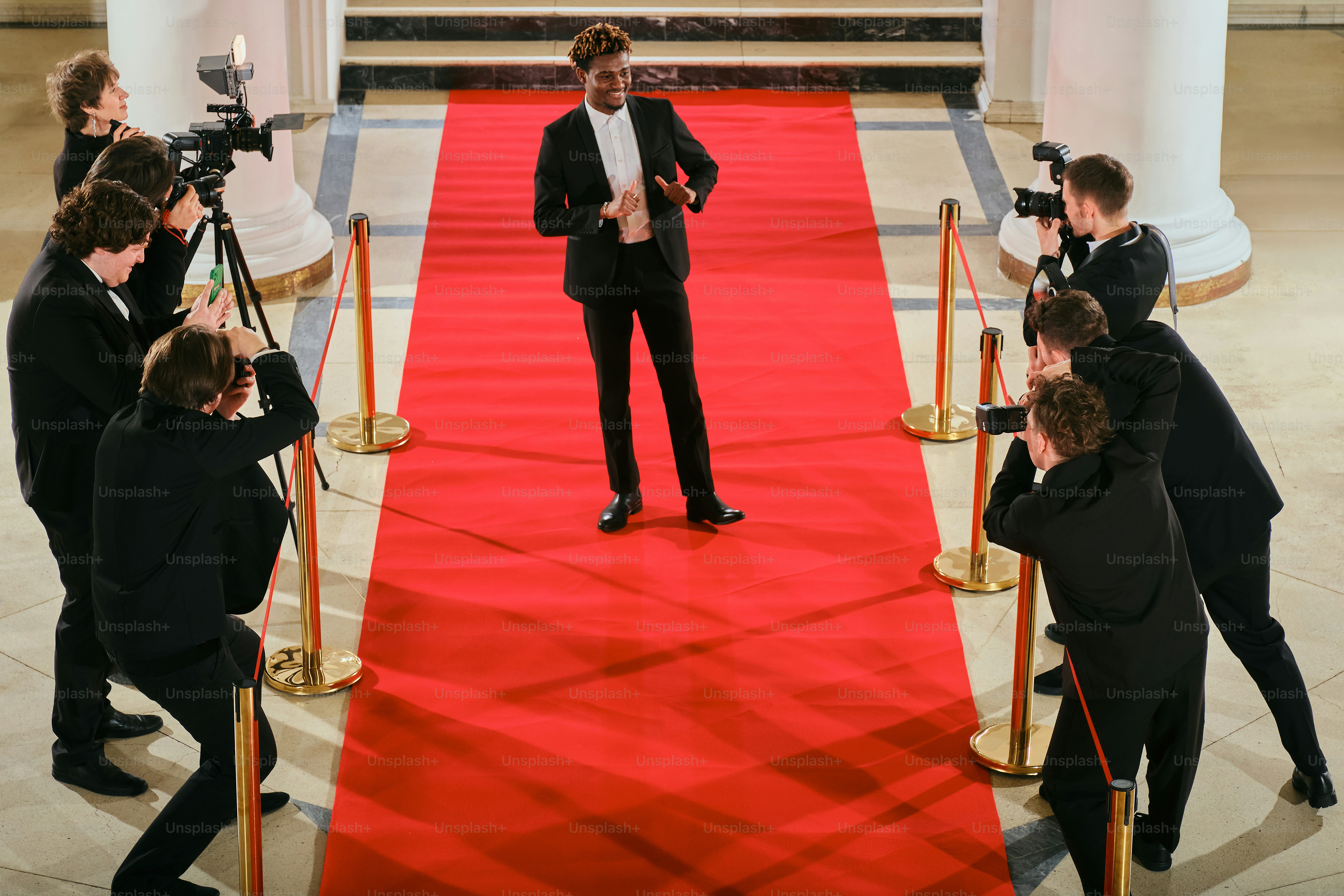 A man standing on a red carpet in front of a camera photo – Celebration ...