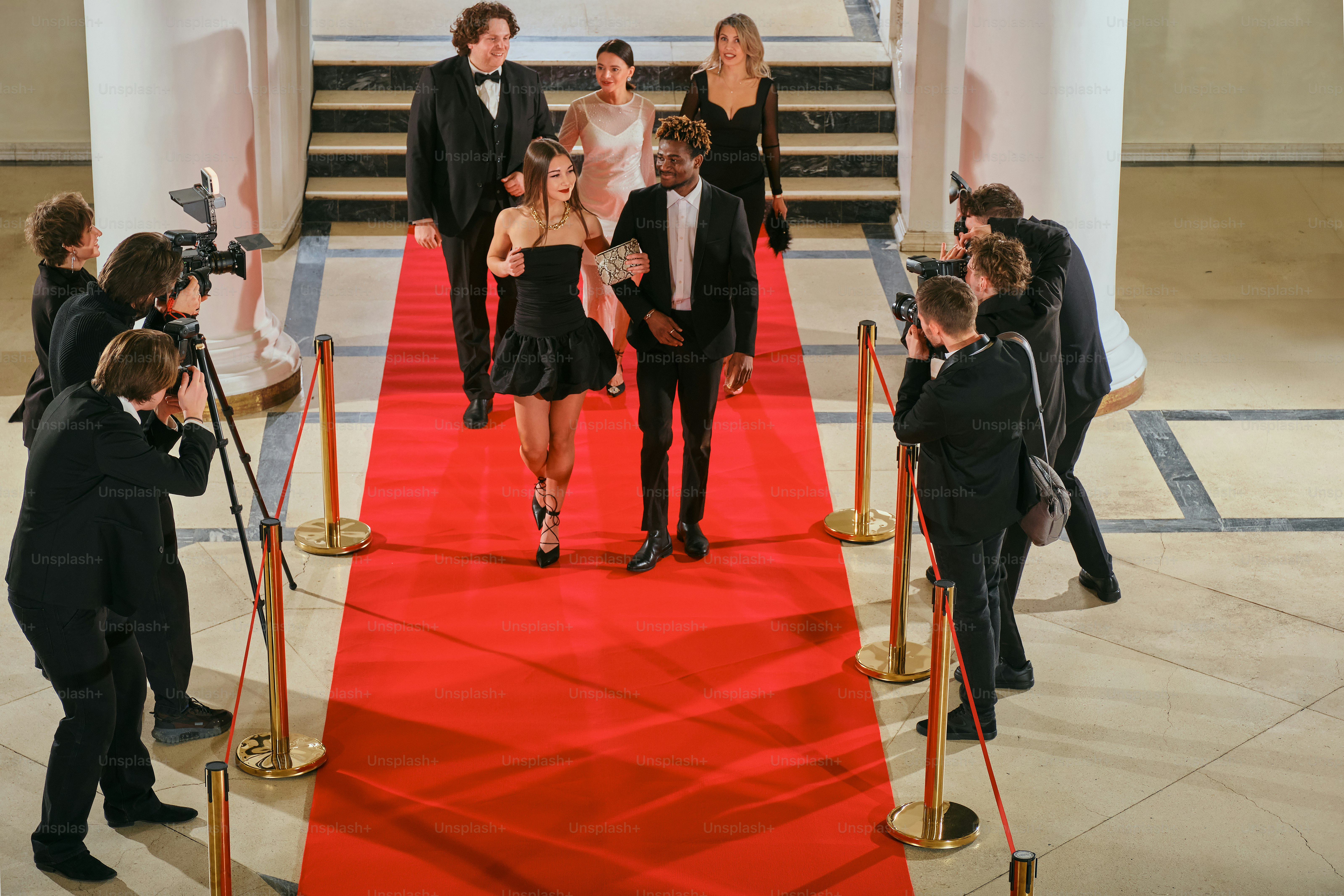 A group of people standing around a red carpet photo – Celebration ...
