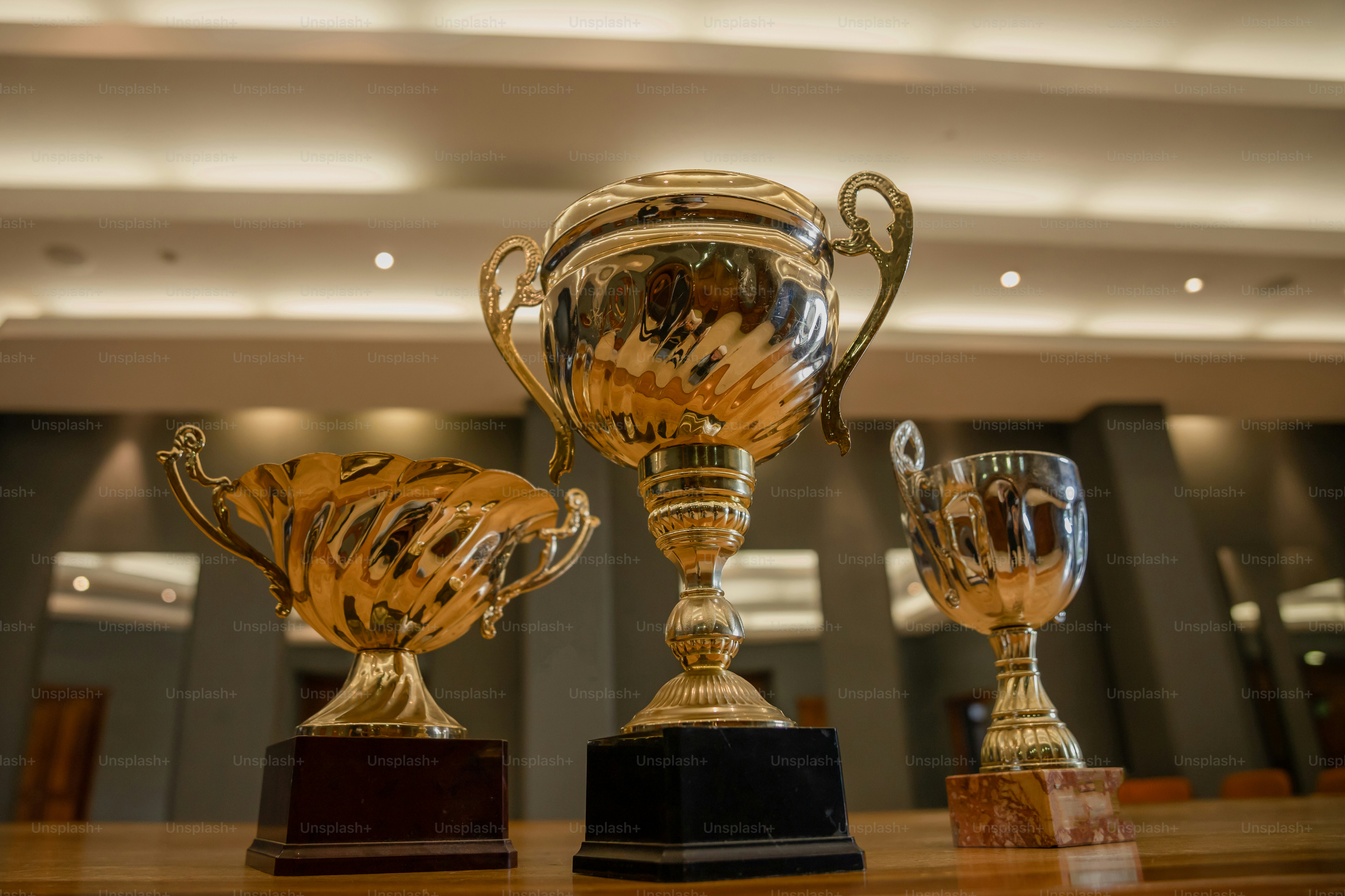 Three trophies sitting on top of a wooden table photo – Celebration ...