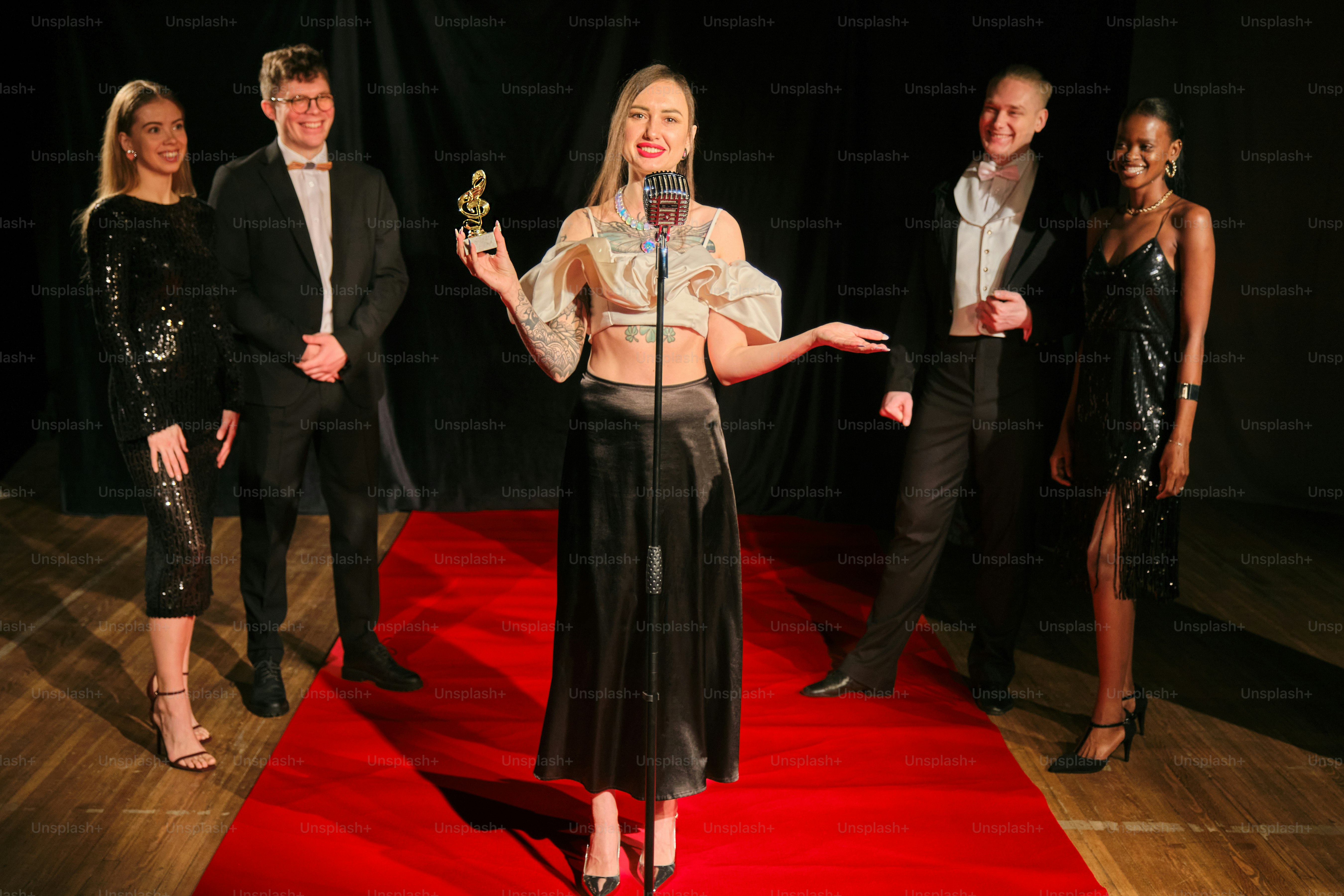 A woman standing on a red carpet holding a microphone photo ...
