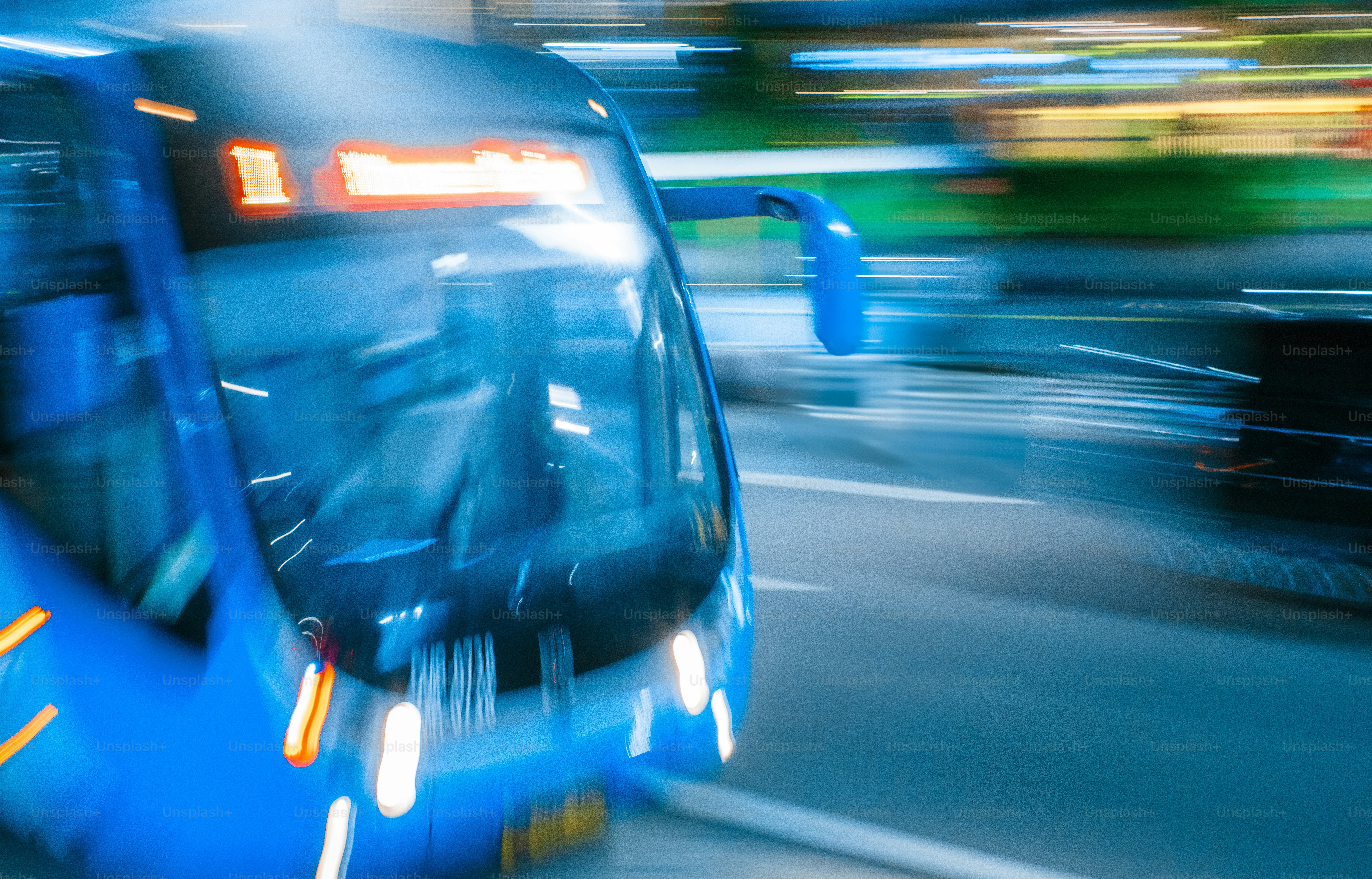 A blue bus driving down a street next to tall buildings photo – Motion ...