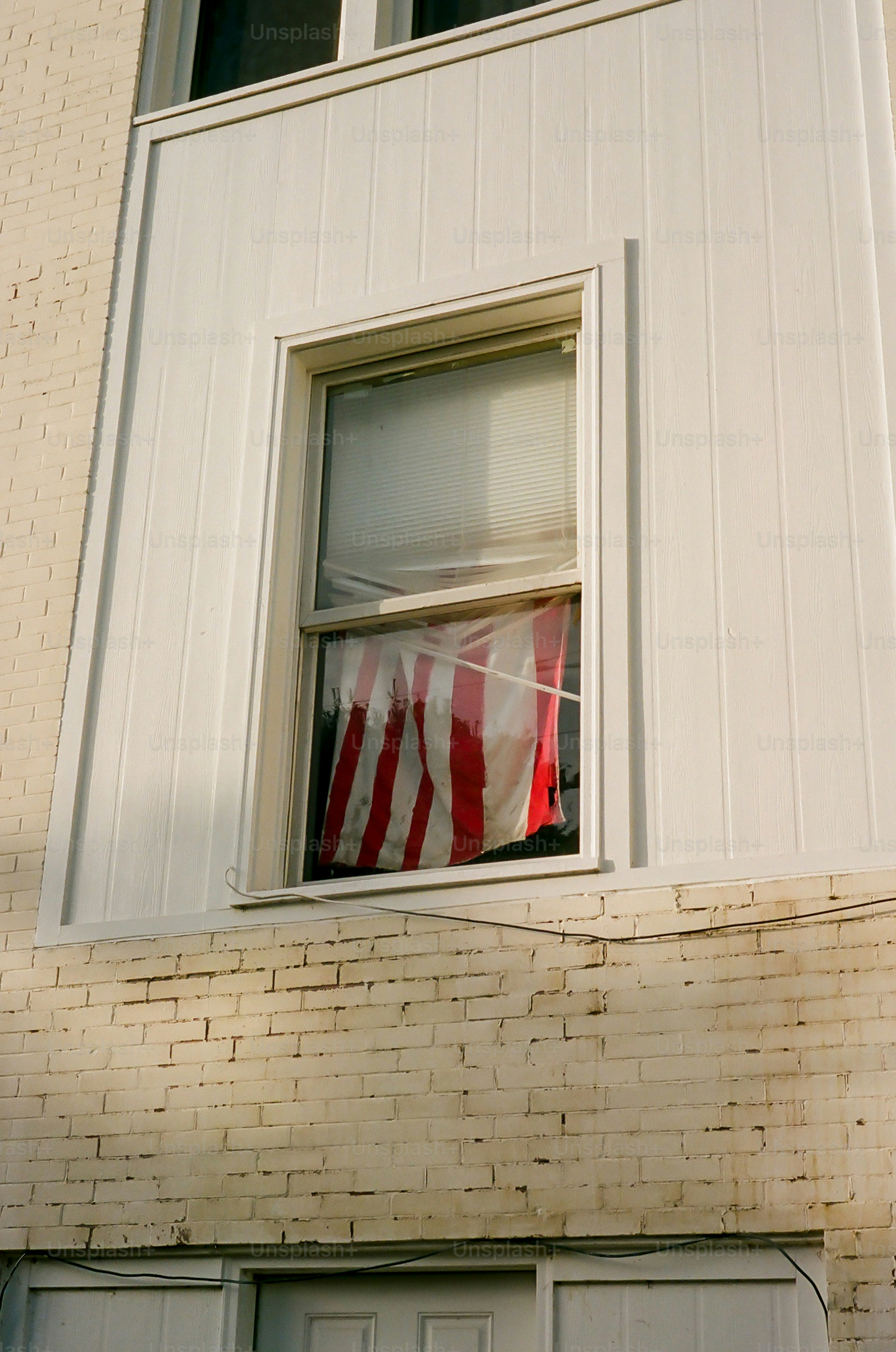 An american flag hanging in a window of a building photo – American ...