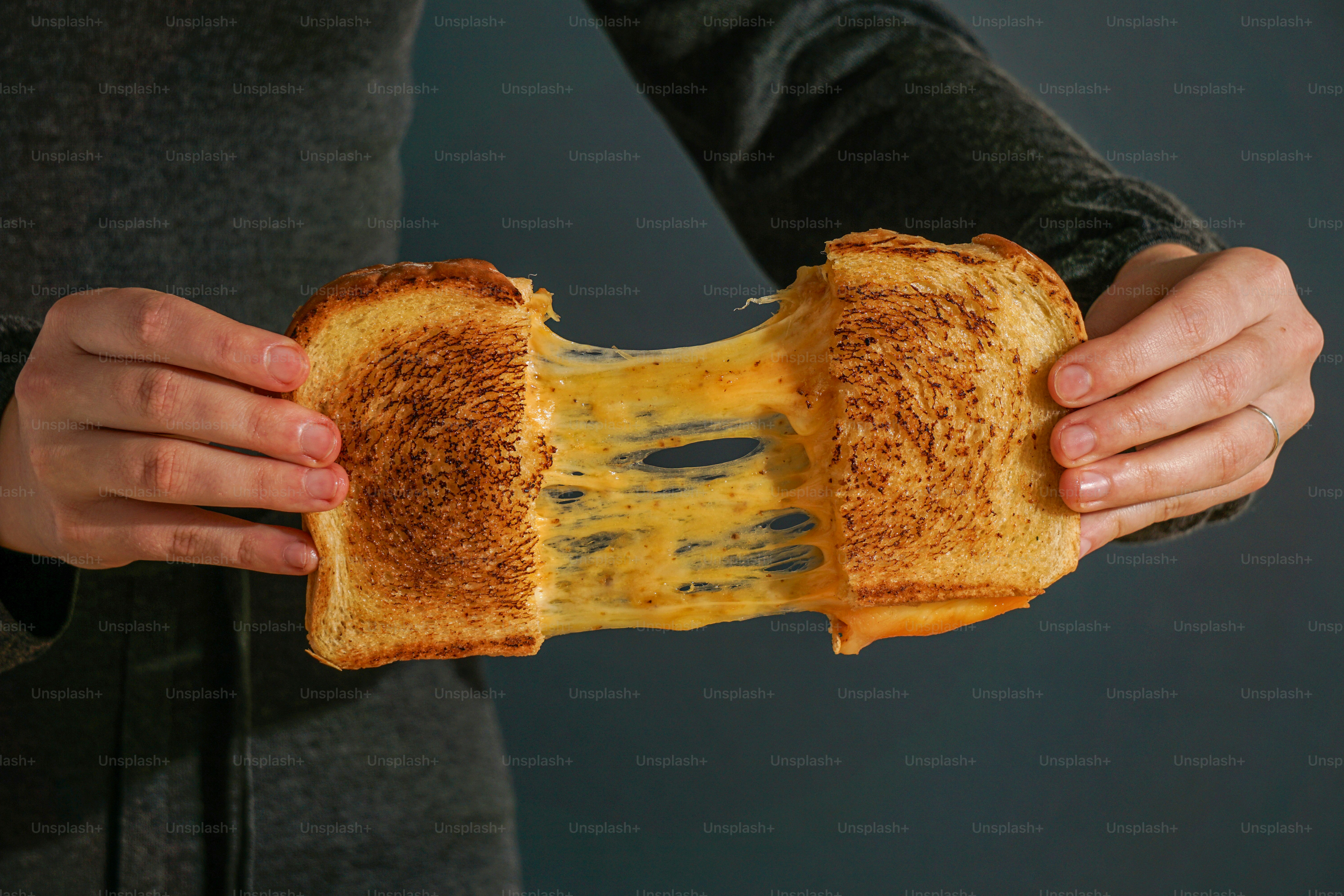 A person holding a piece of bread in their hands photo – Cheese toast ...