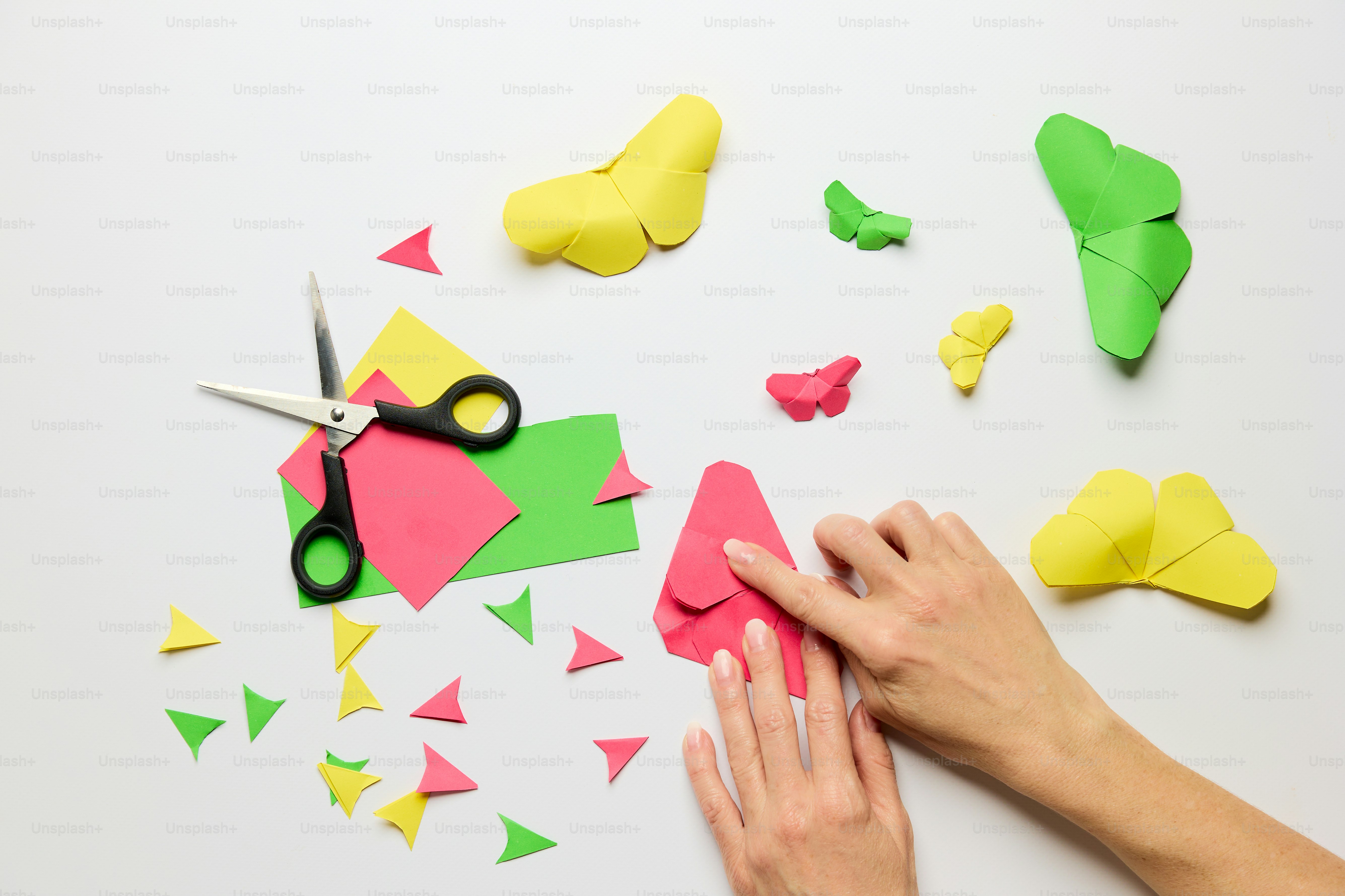 A person cutting paper with scissors on a table photo – Art Image on ...