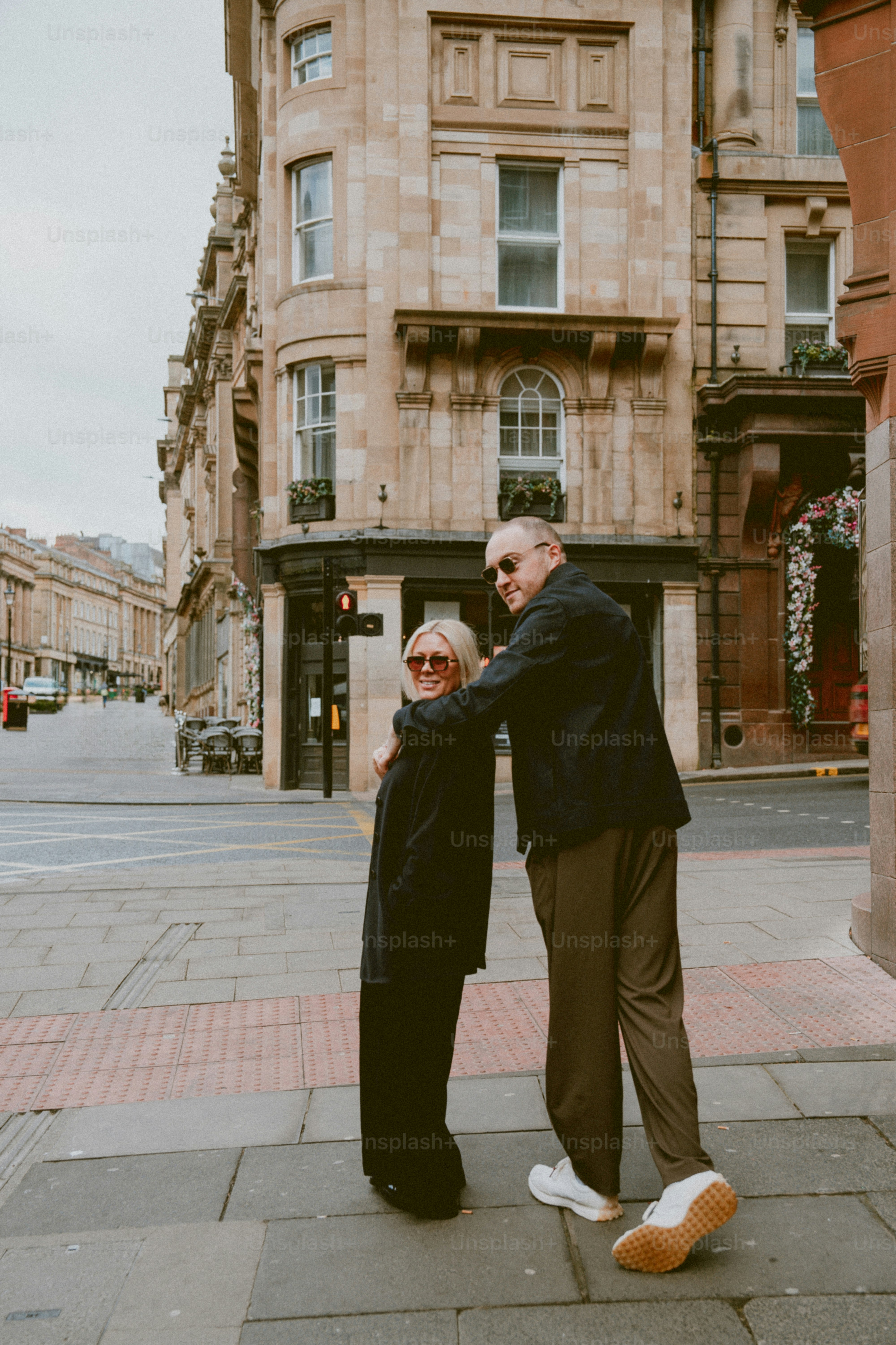 Couple poses on a city street corner. photo – Portrait Image on Unsplash