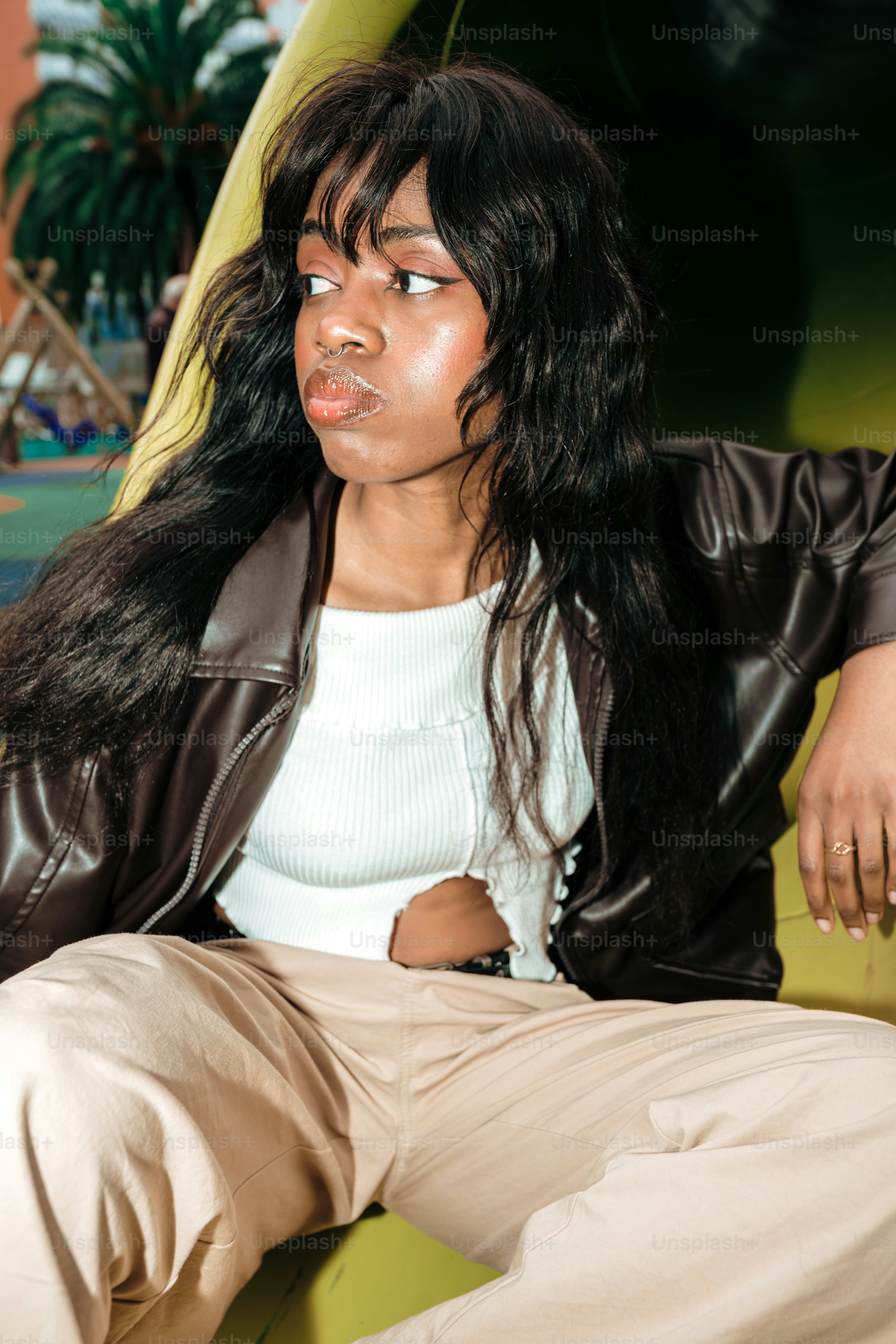 A woman in a leather jacket sitting on a green chair photo – Beauty ...
