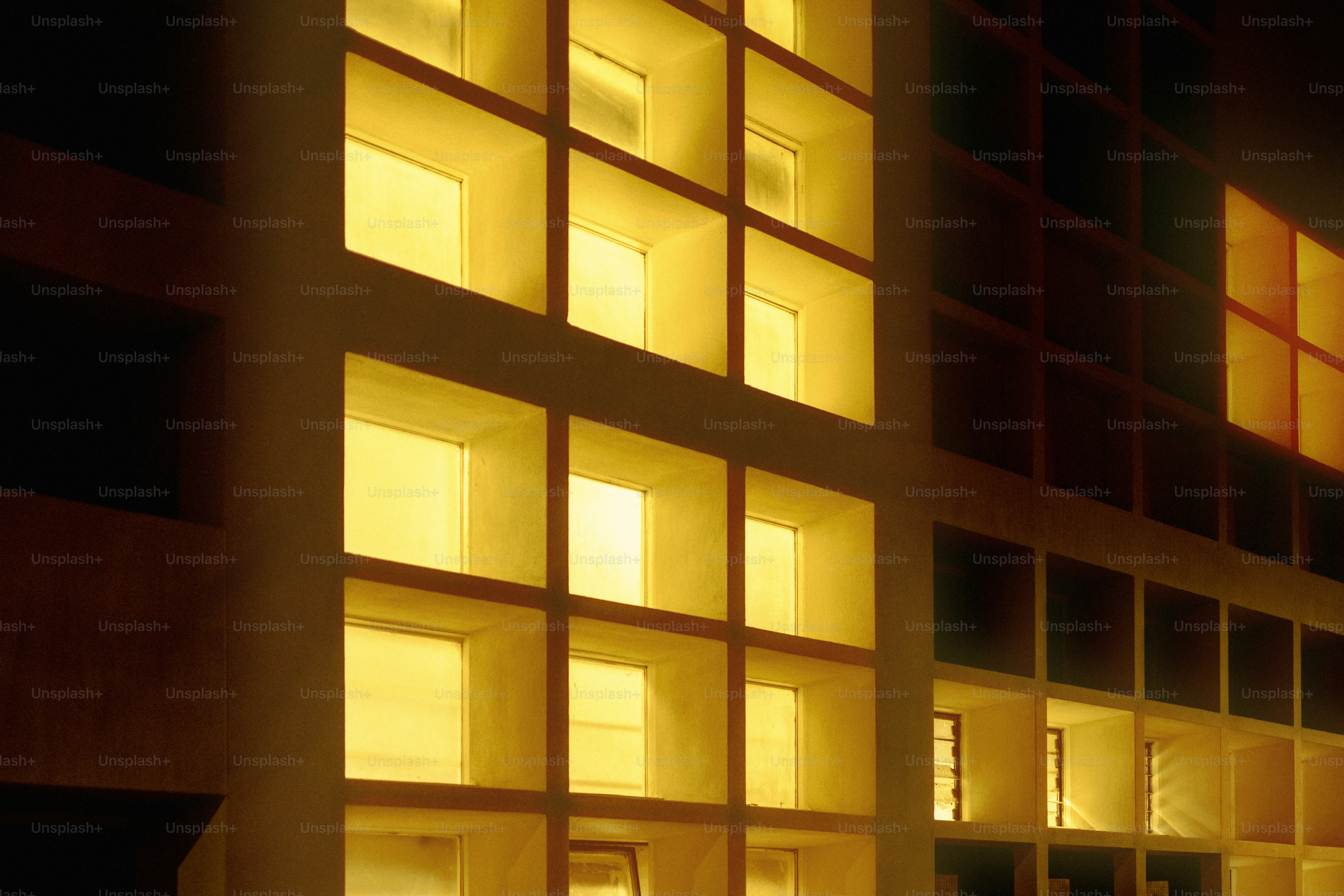 A building with a lot of windows lit up at night photo – City Image on ...