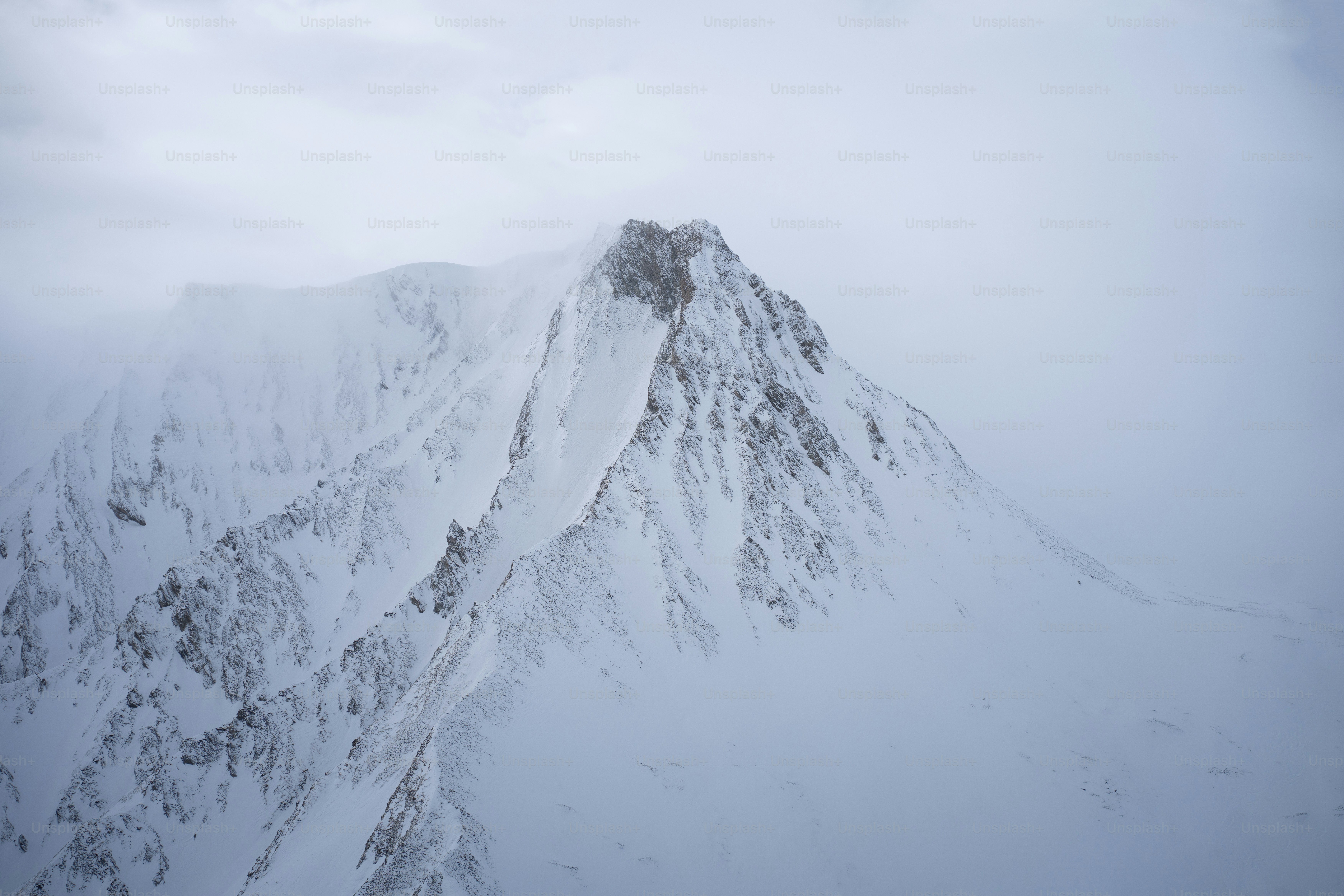 A very tall mountain covered in snow under a cloudy sky photo – Clouds ...
