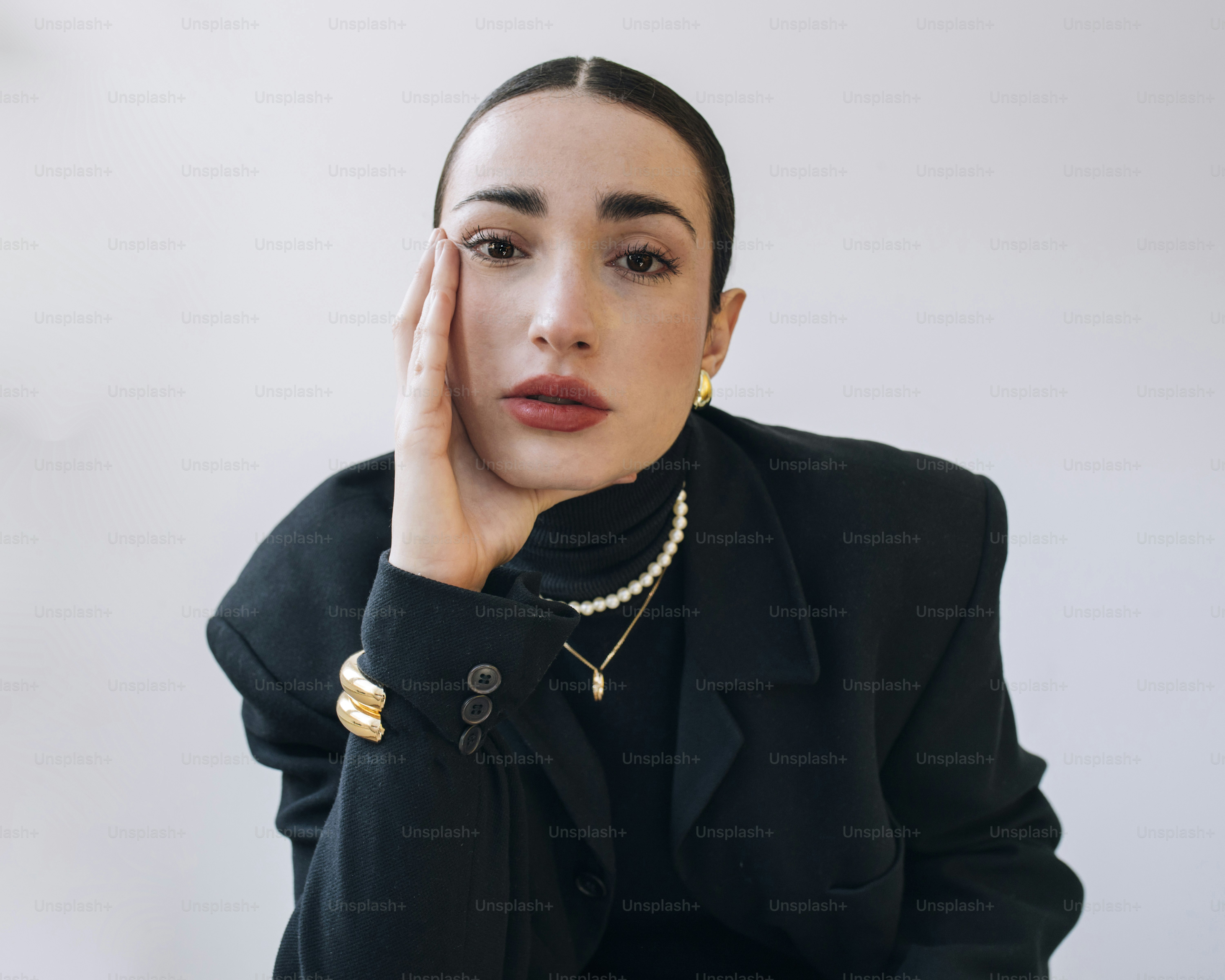 Una mujer con traje negro sentada con la mano en la cara foto – Imagen ...