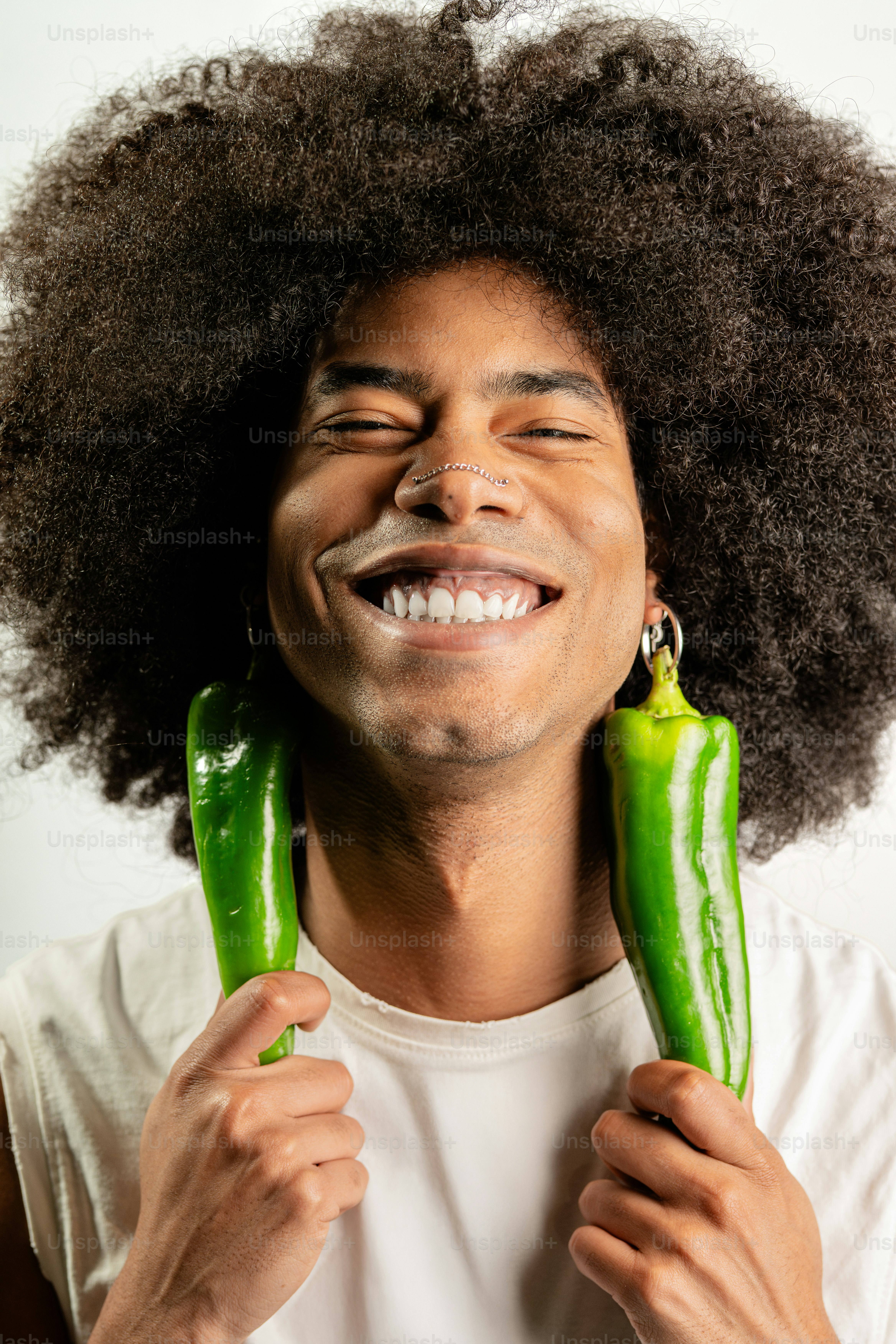 A man holding two green peppers up to his face photo – Food Image on ...