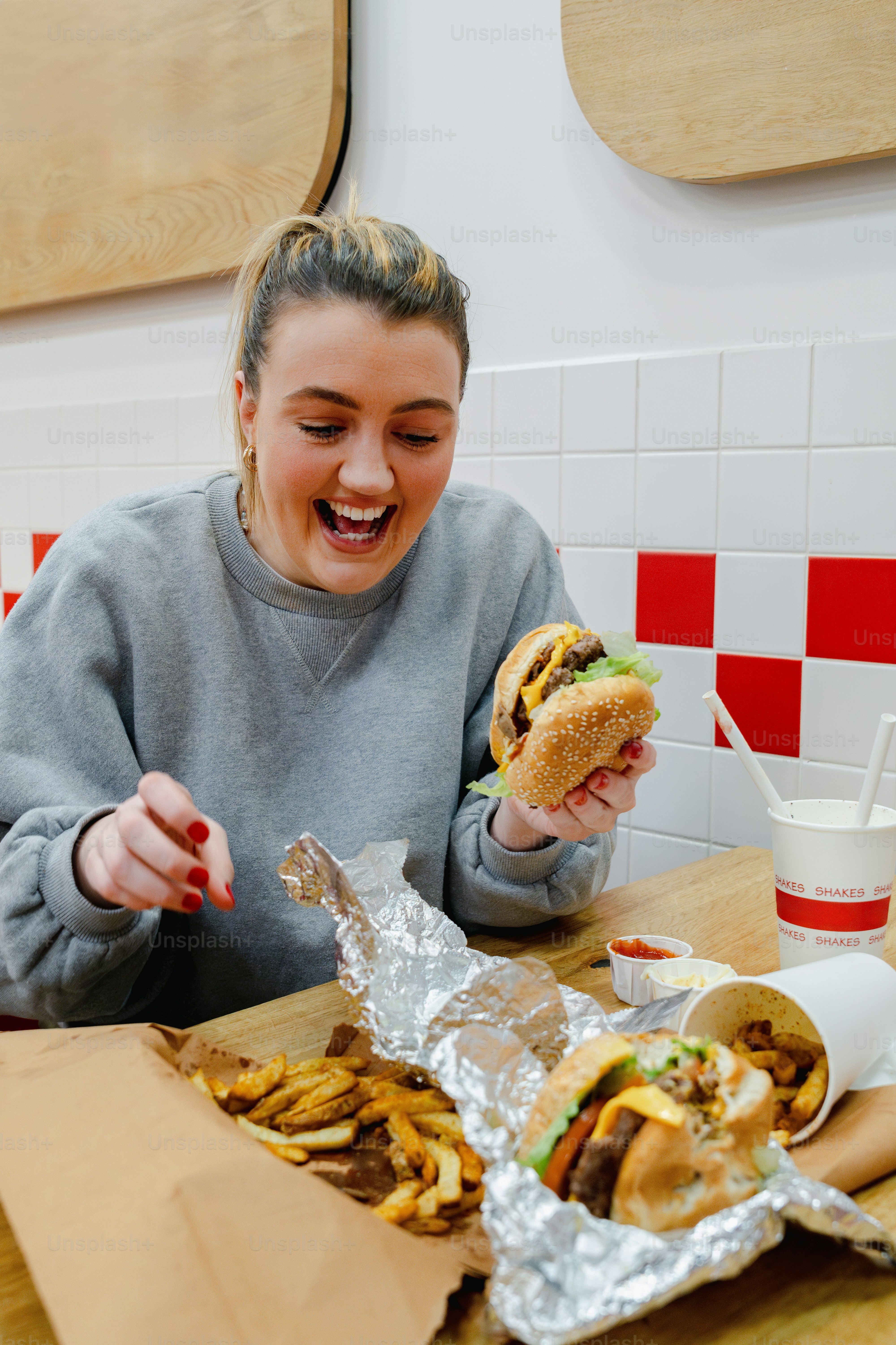 A woman sitting at a table eating a sandwich photo – Food Image on Unsplash