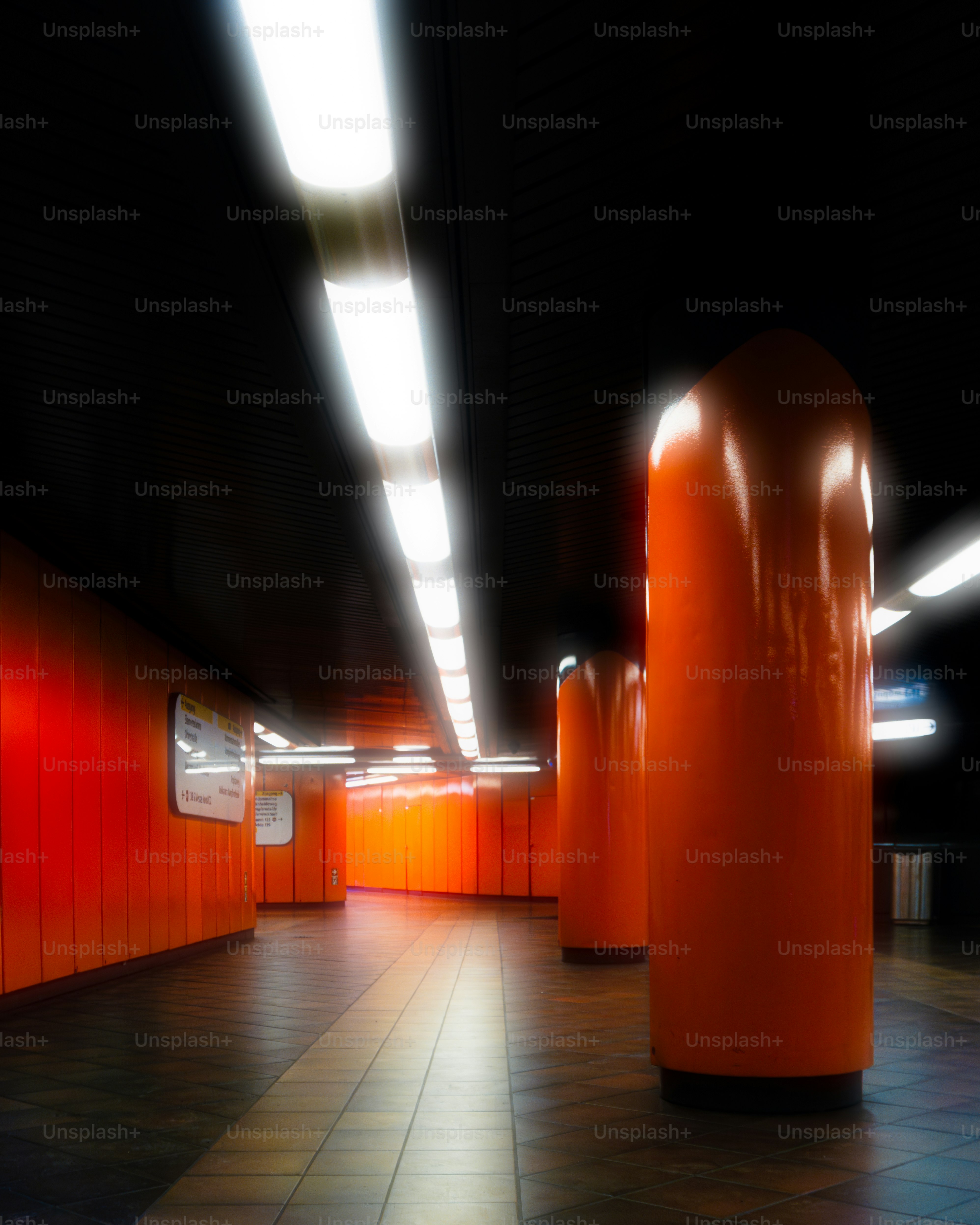 A long hallway with orange columns and lights photo – City Image on ...