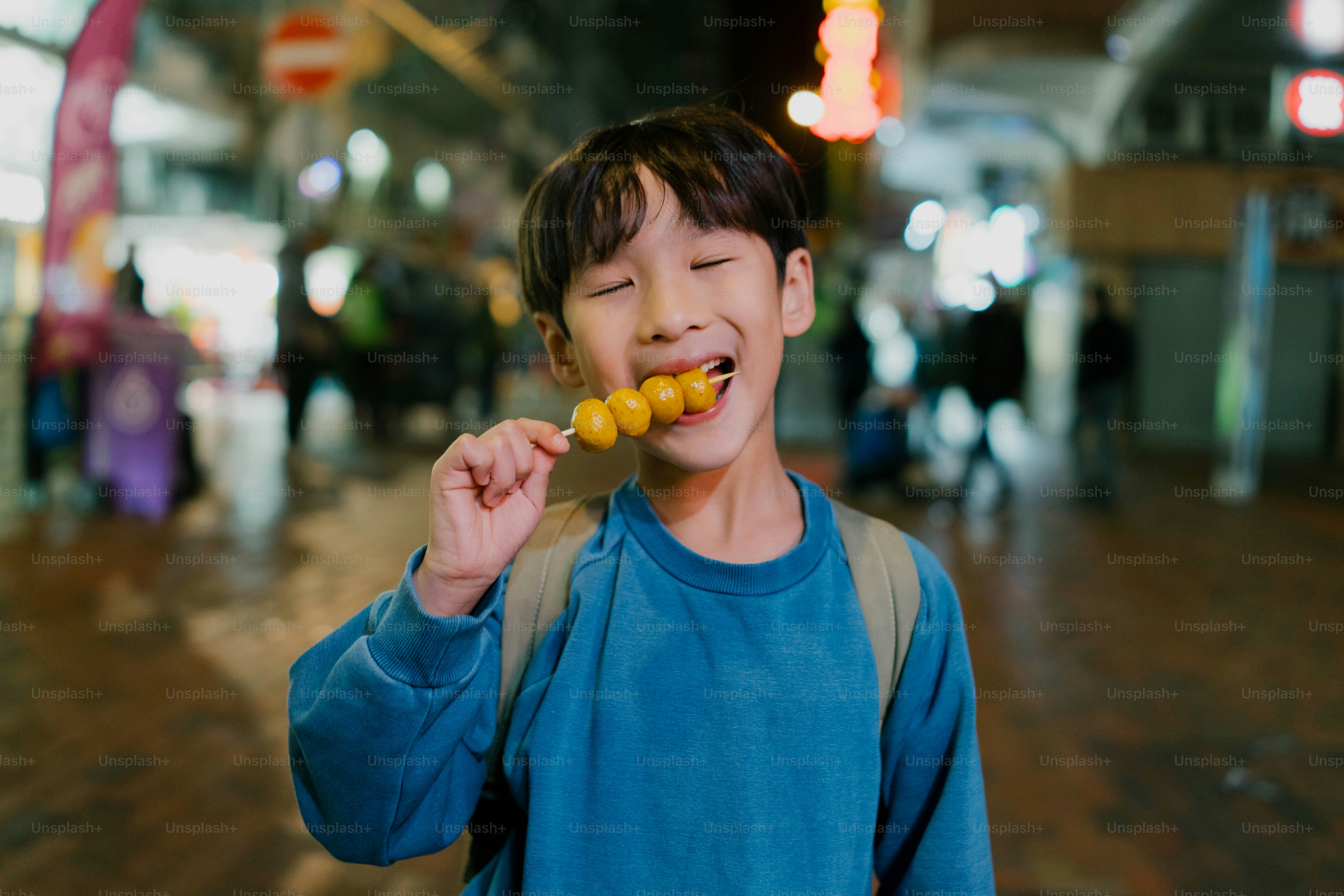 A young boy eating something with his hands photo – Travel Image on ...