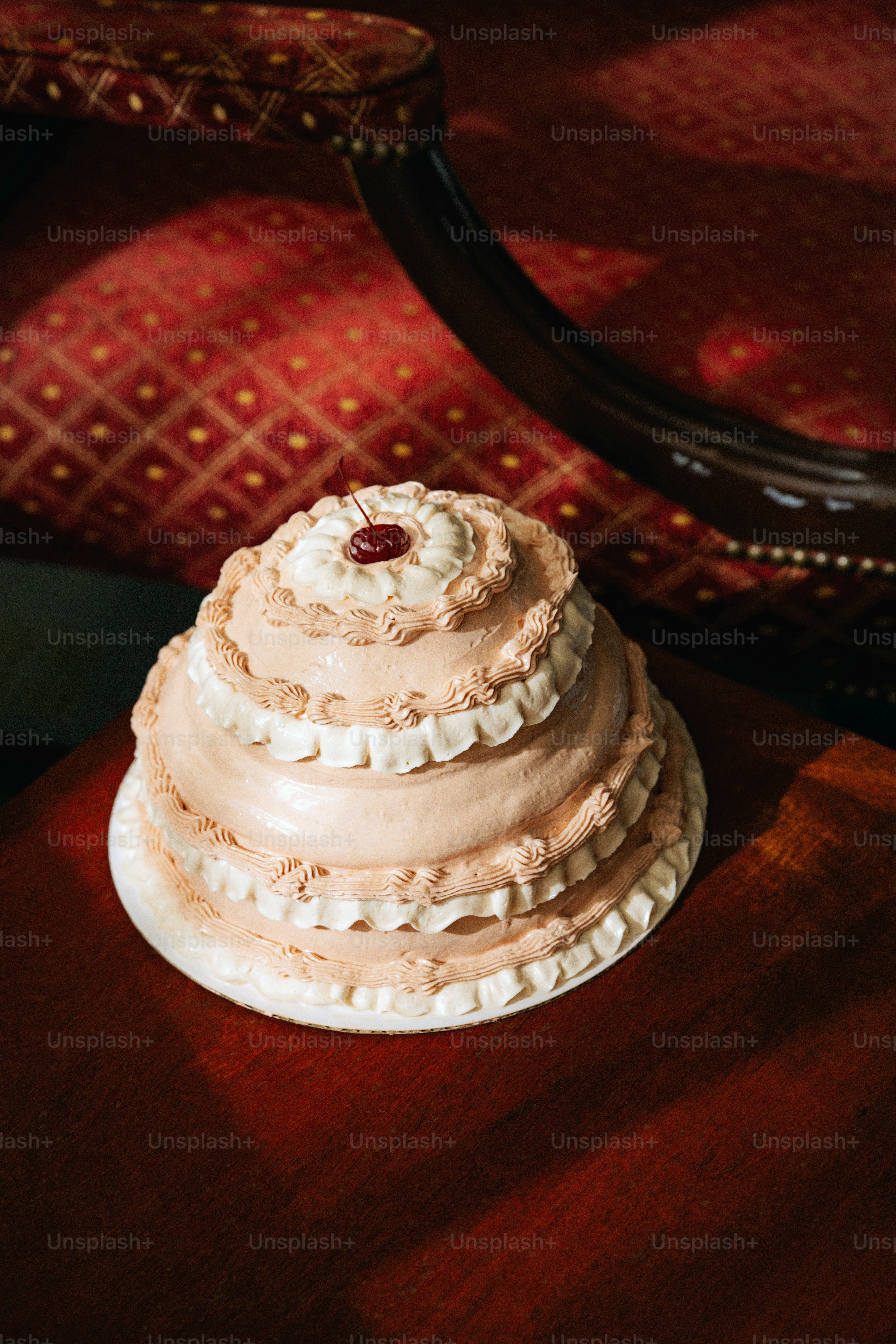 A fancy, tiered cake rests on a table. photo – Cake Image on Unsplash