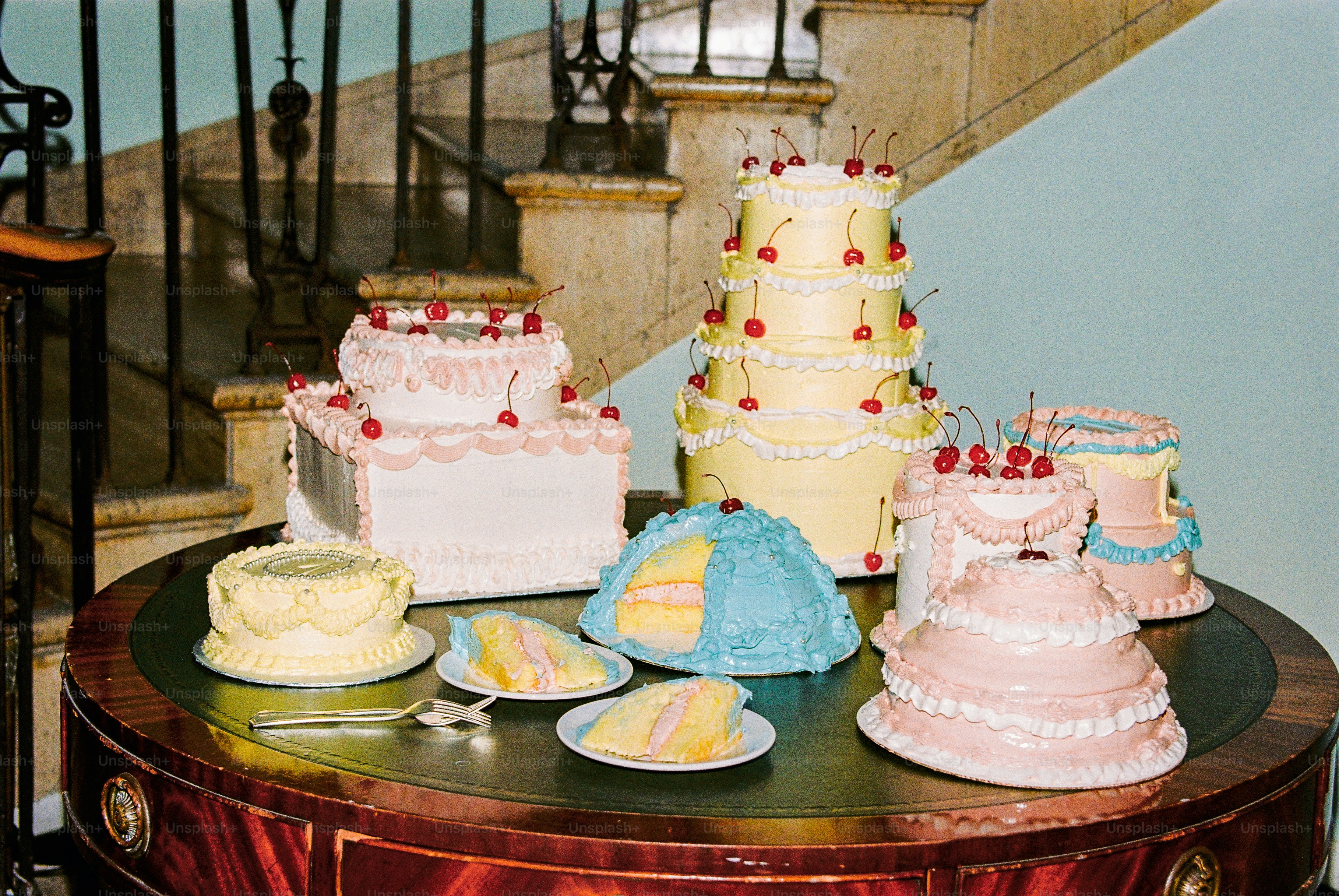 Several fancy cakes displayed on a round table. photo – Cake Image on ...