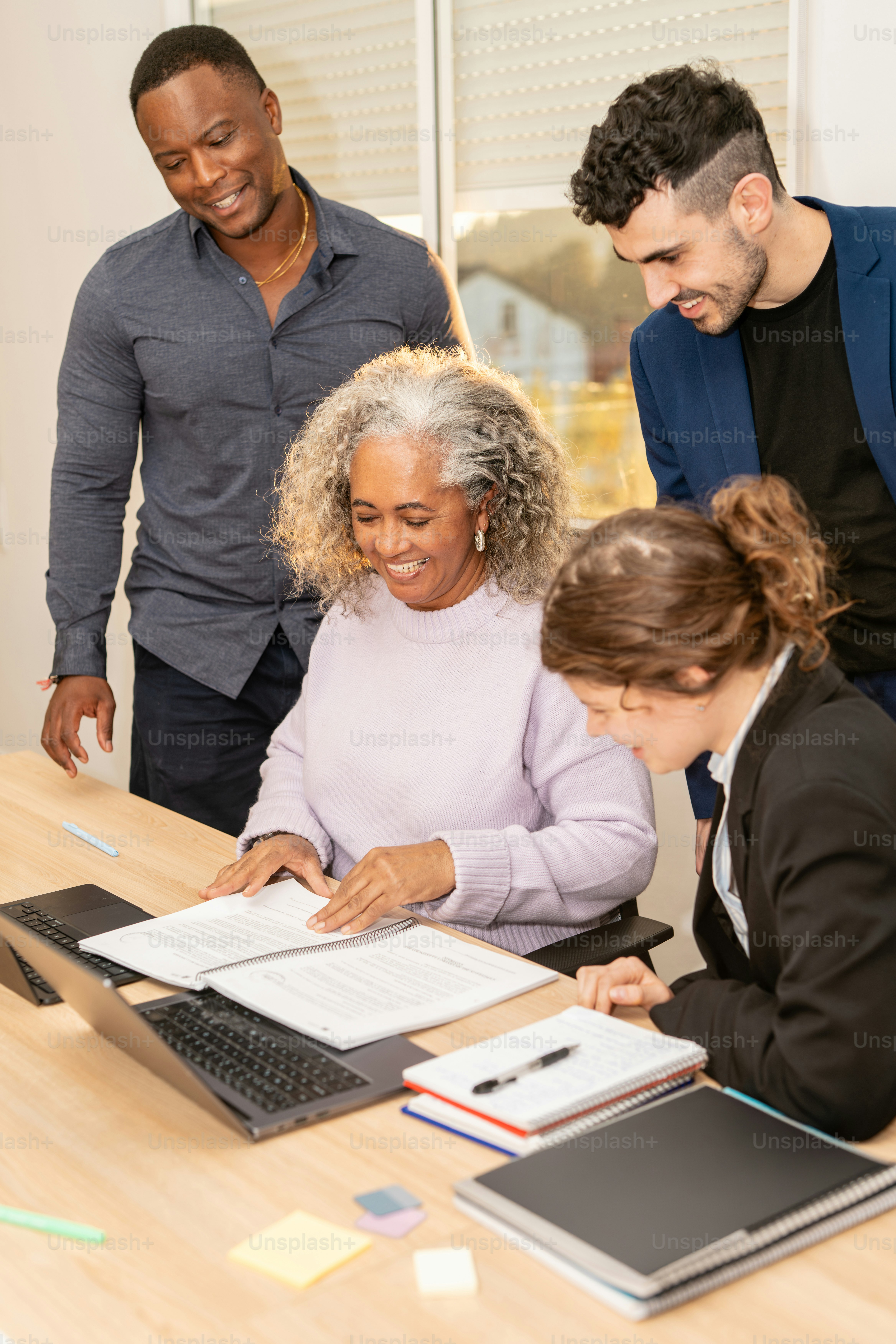 A diverse group of people review documents together. photo – Leadership ...