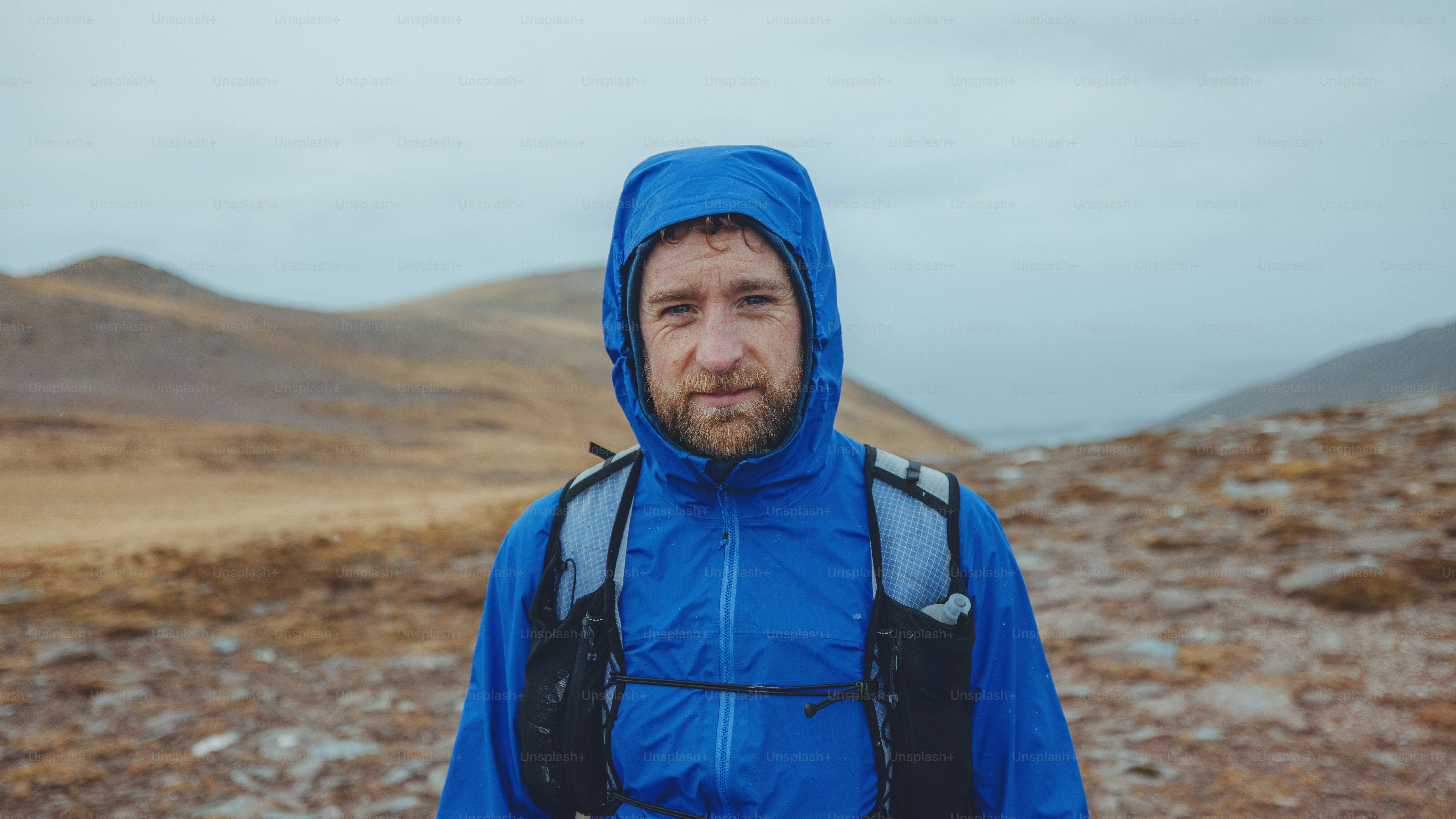 Man wears a blue rain jacket in a barren landscape. photo – Wallpaper ...