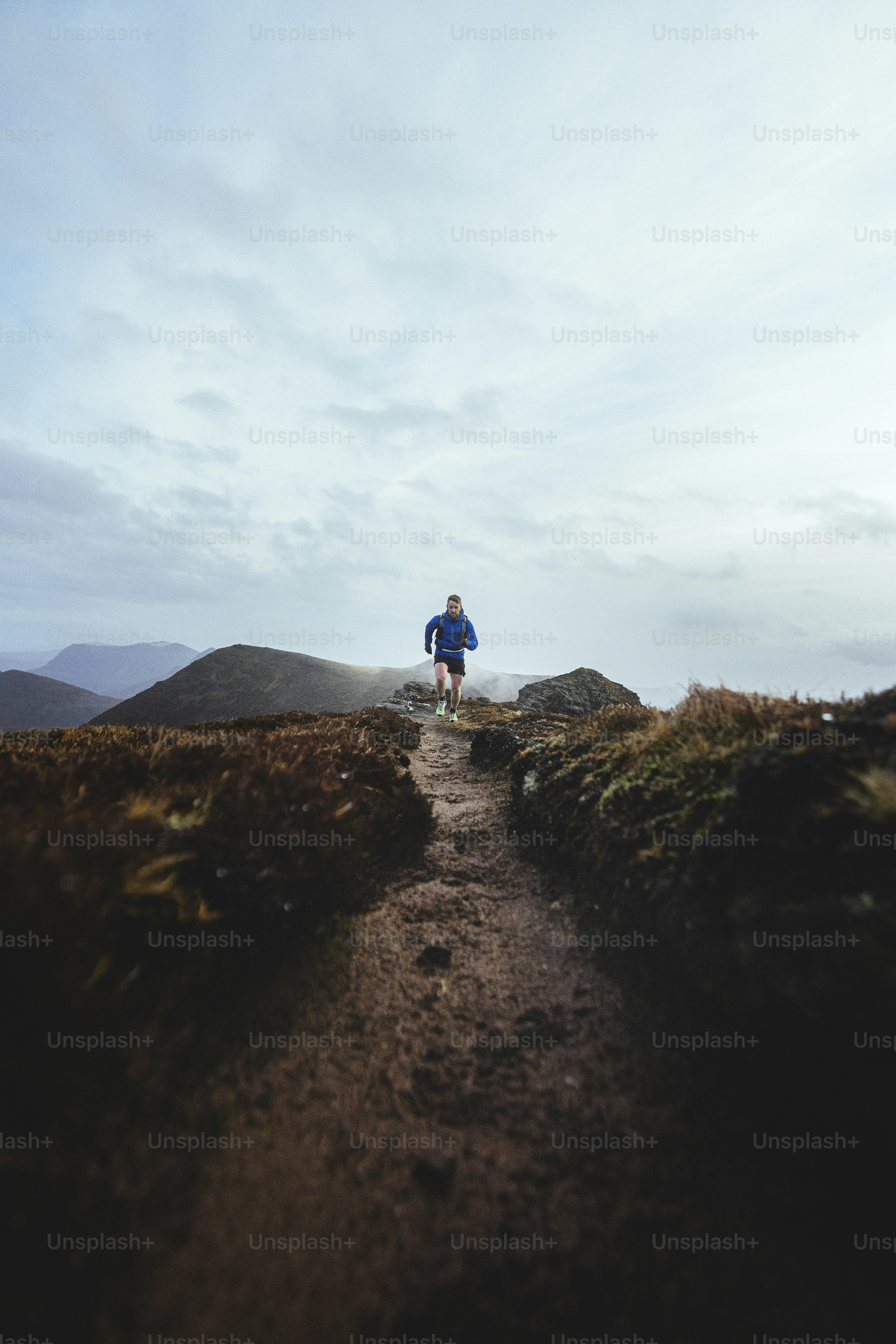 Runner sprints across a mountain path in open landscape. photo ...