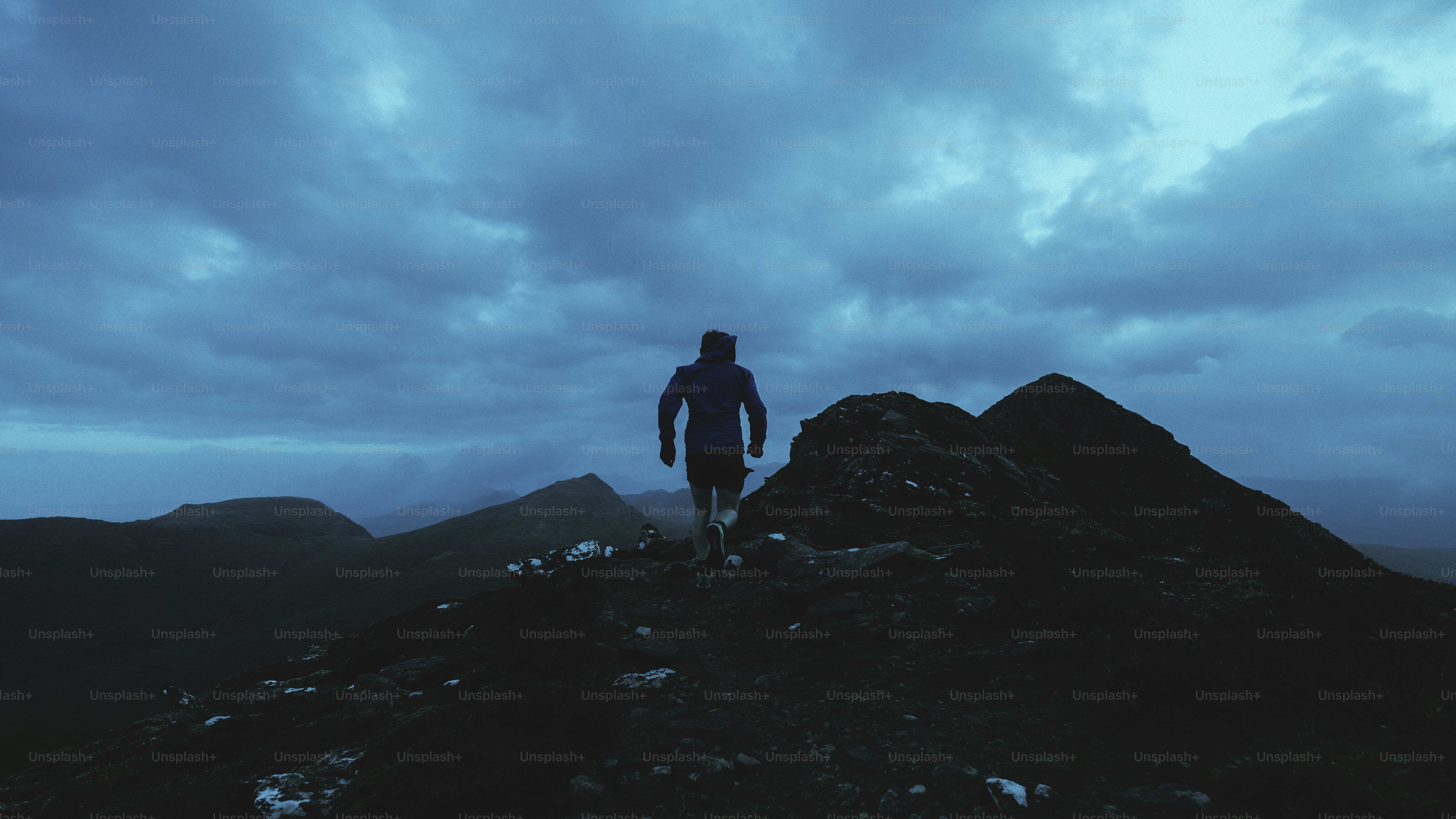 A lone runner ascends a mountain under ominous skies. photo – Wallpaper ...