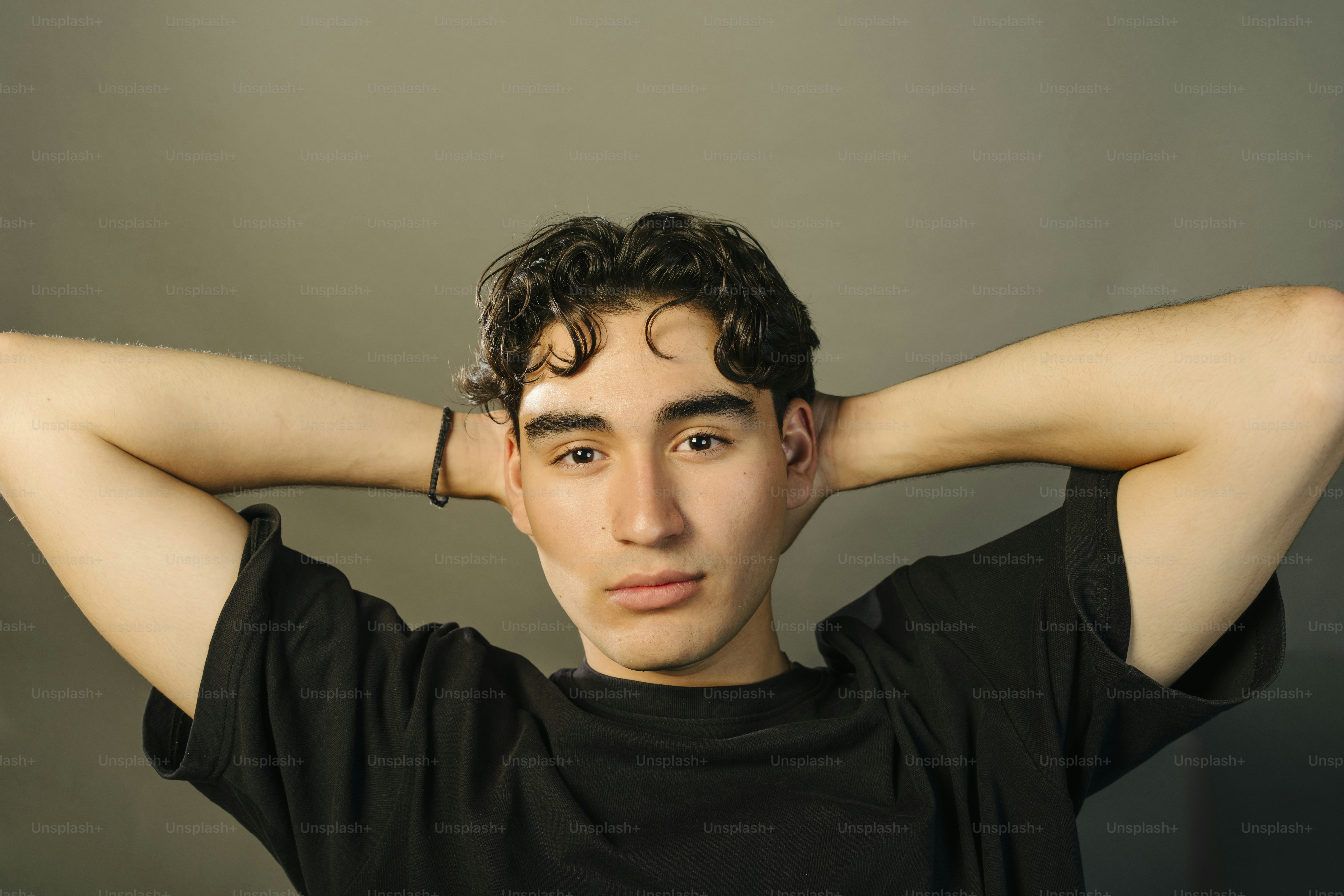 A young man poses with hands behind head. photo – Haircut Image on Unsplash