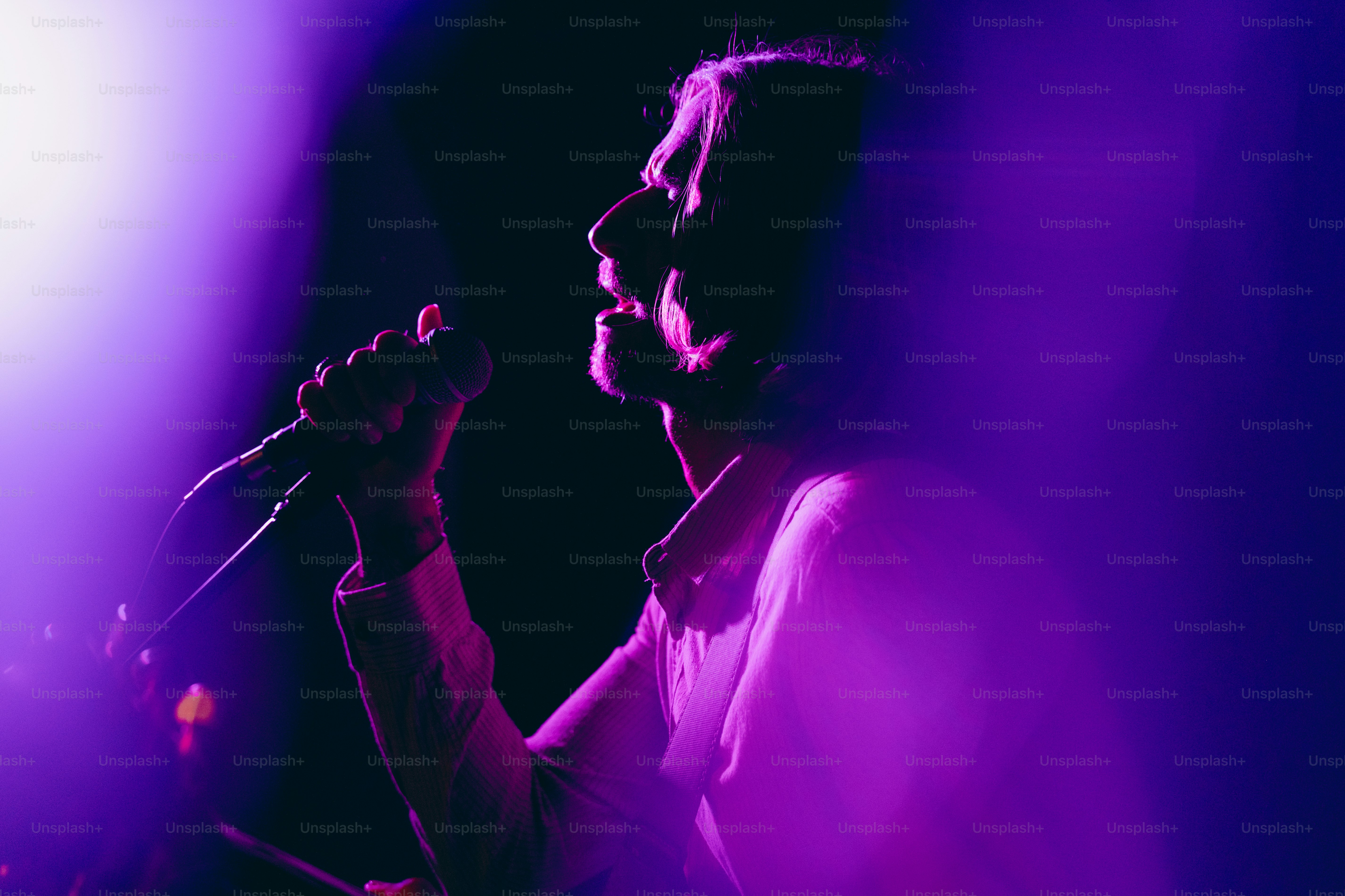 A singer performs under purple stage lights. photo – Man Image on Unsplash