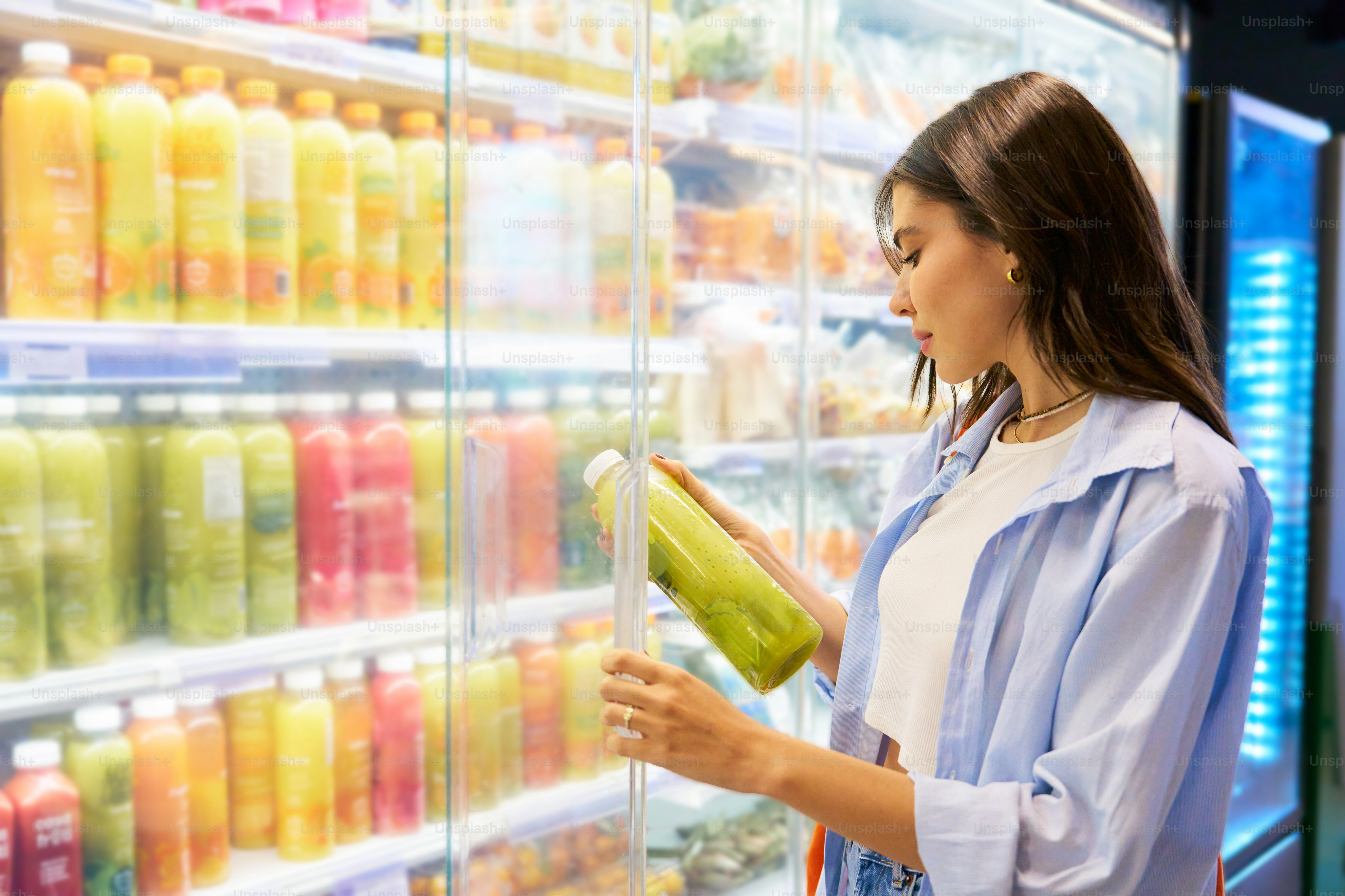 Woman chooses a healthy juice from a refrigerated display. photo ...