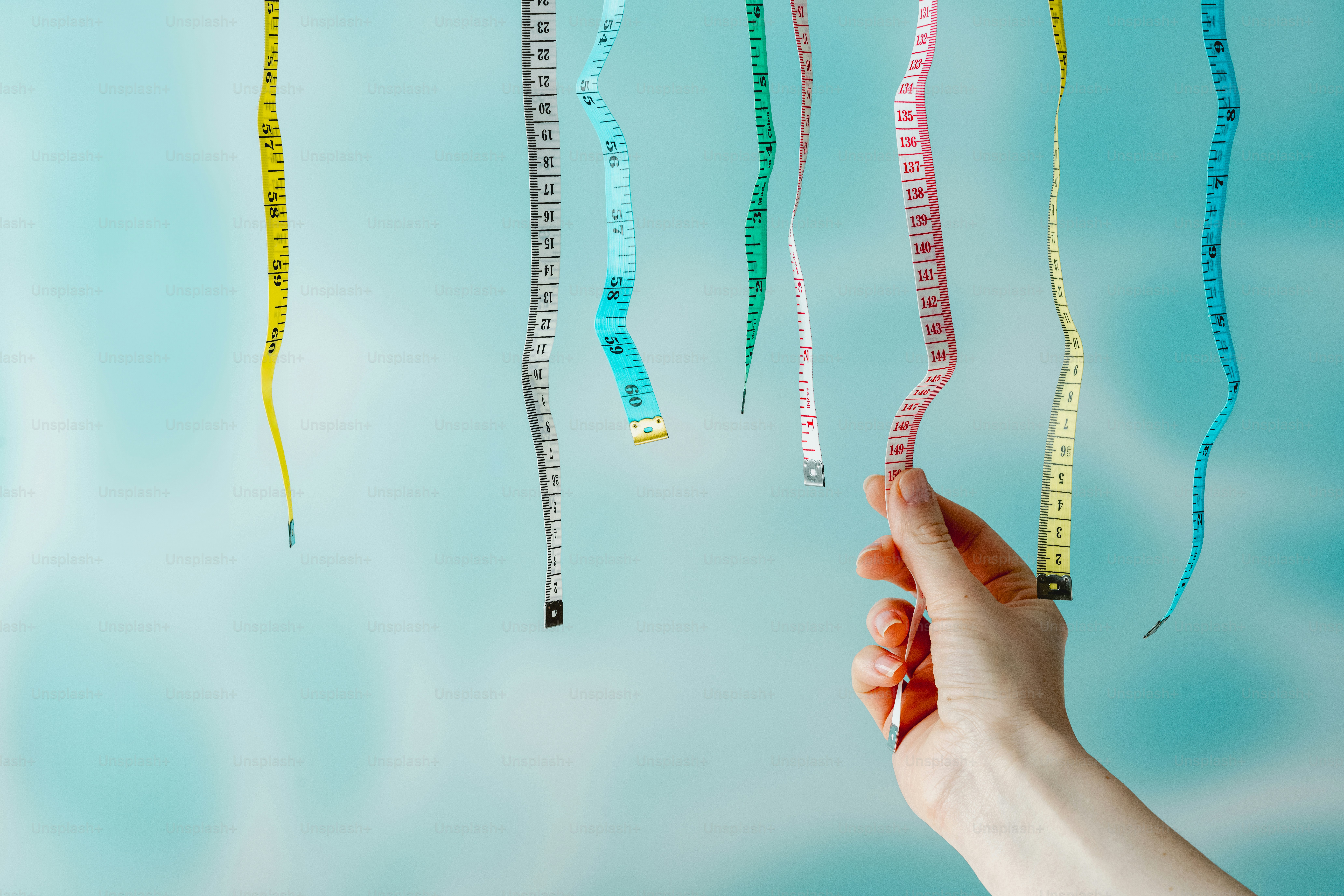 A hand selects a measuring tape from above. photo – Food Image on Unsplash