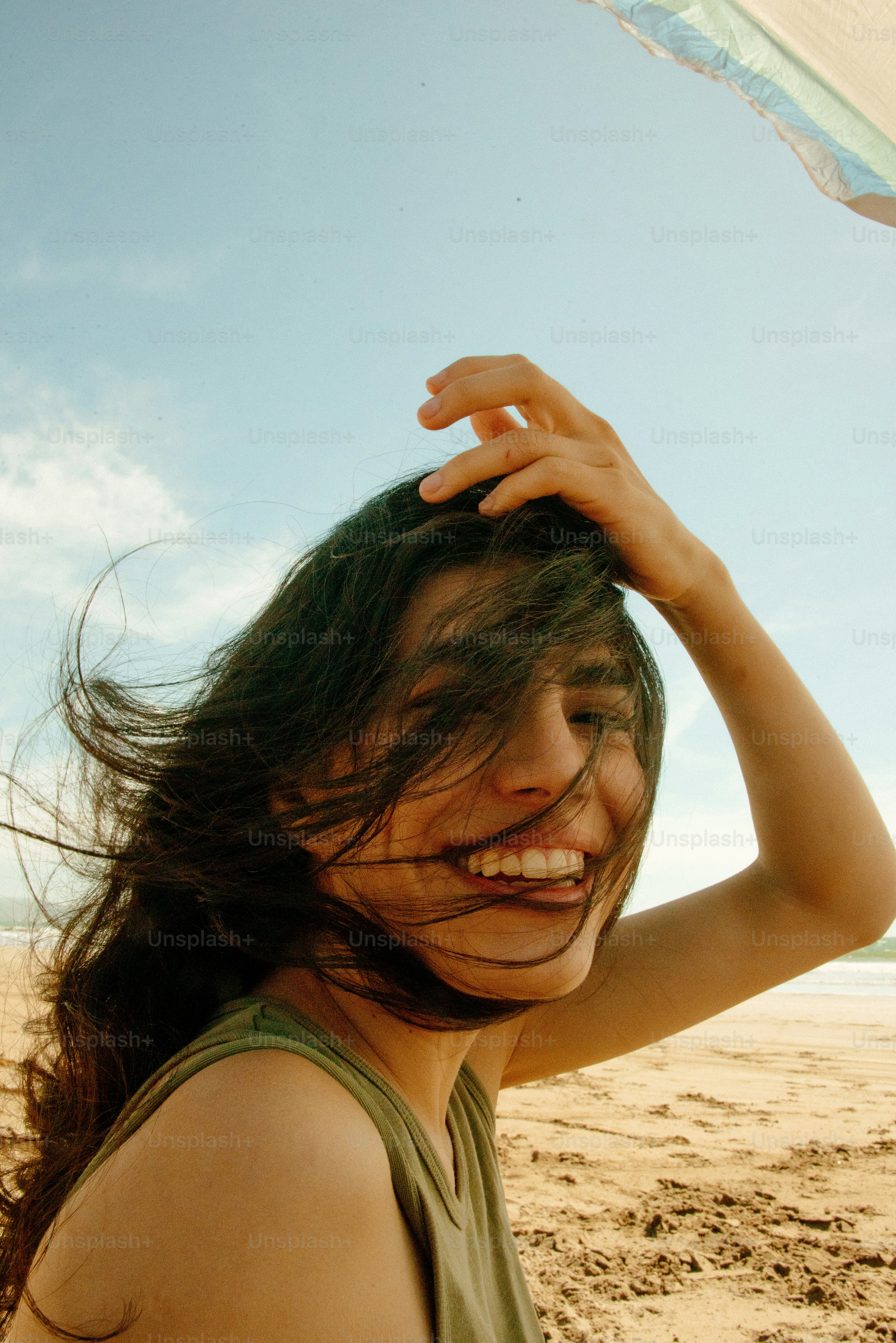 A happy woman enjoys the sunny, windy beach. photo – Beach Image on ...