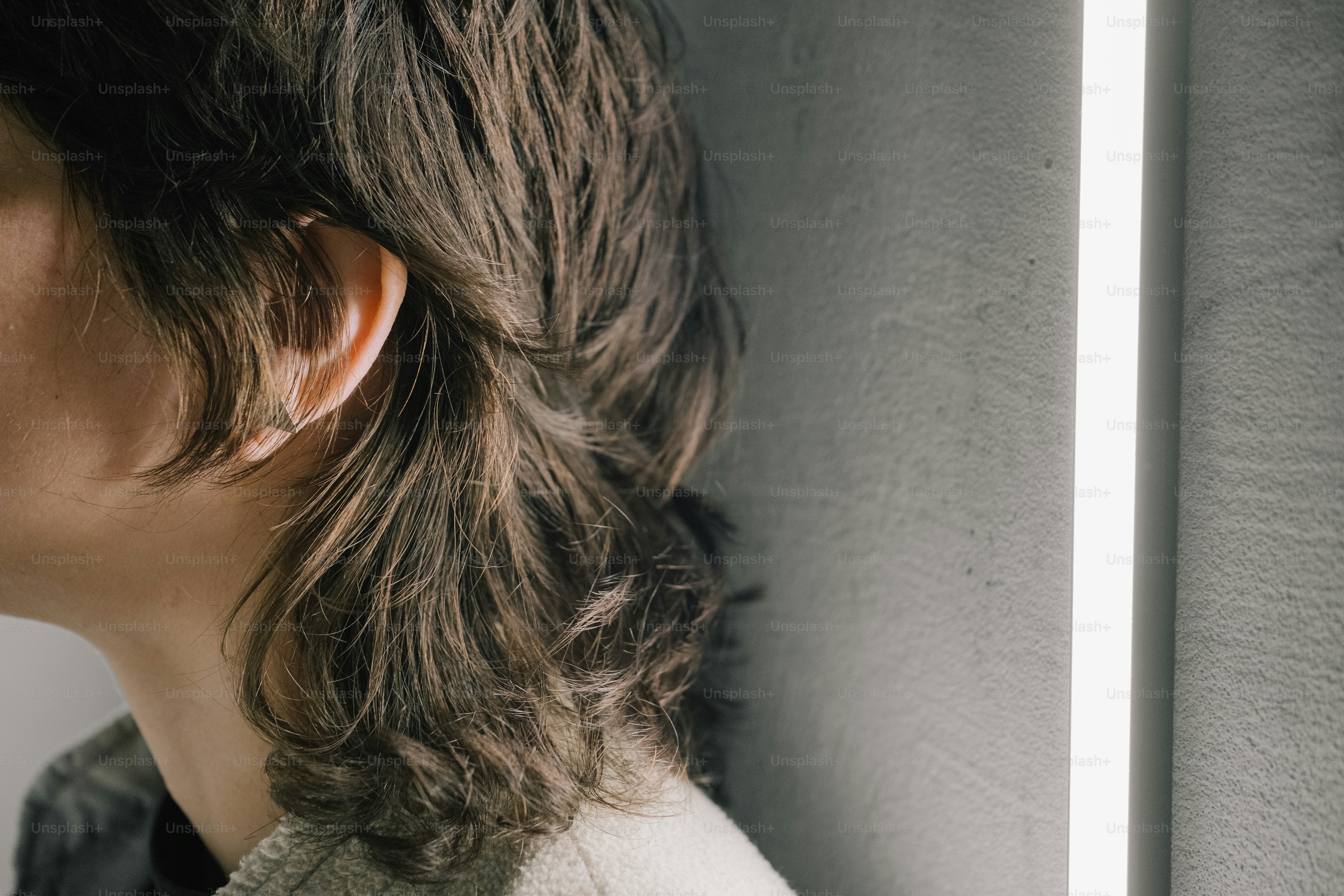 A person's ear and hair in a gray space. photo – Portrait Image on Unsplash