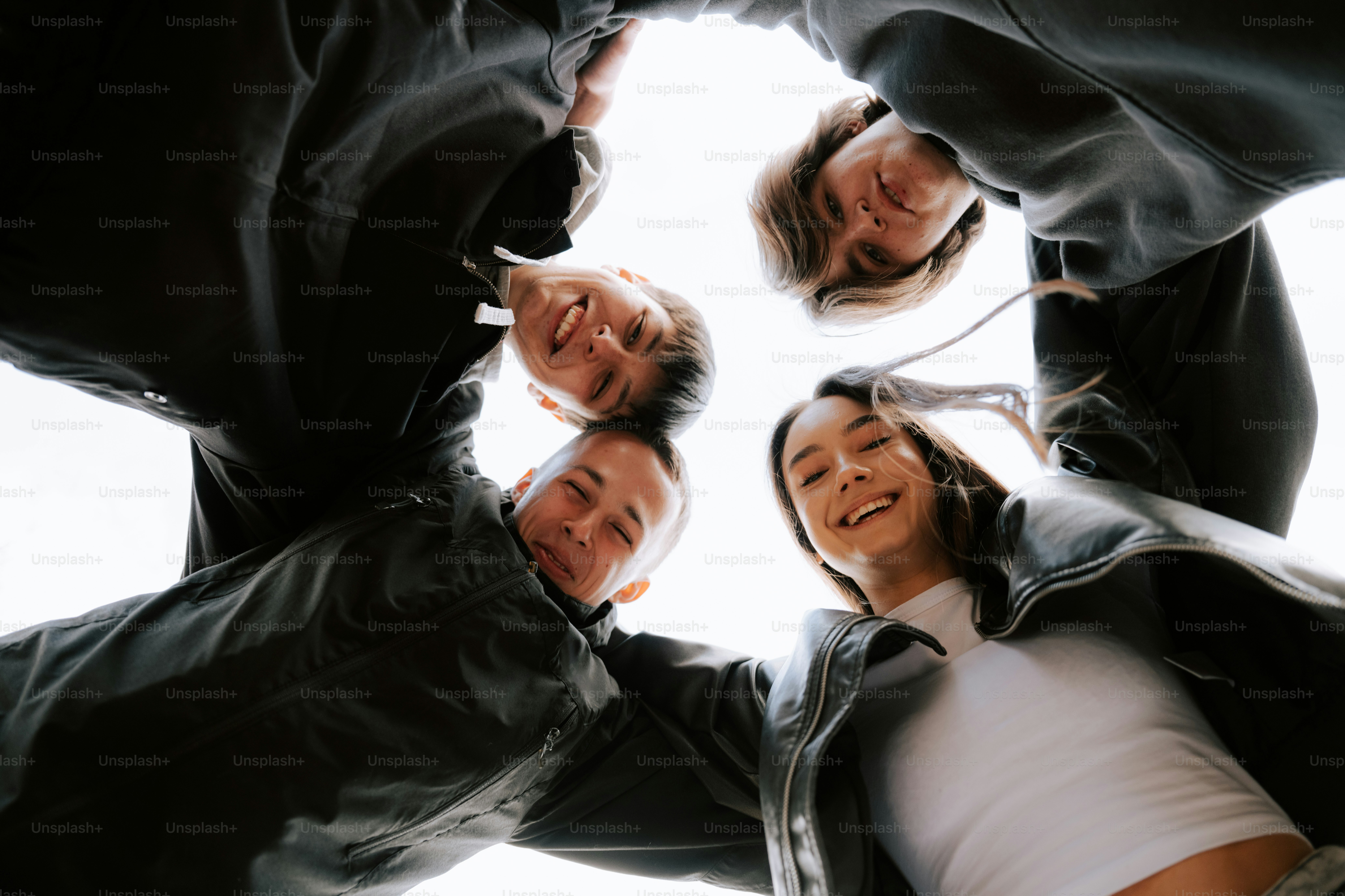 Friends huddled together, smiling and looking up. photo – Diversity ...