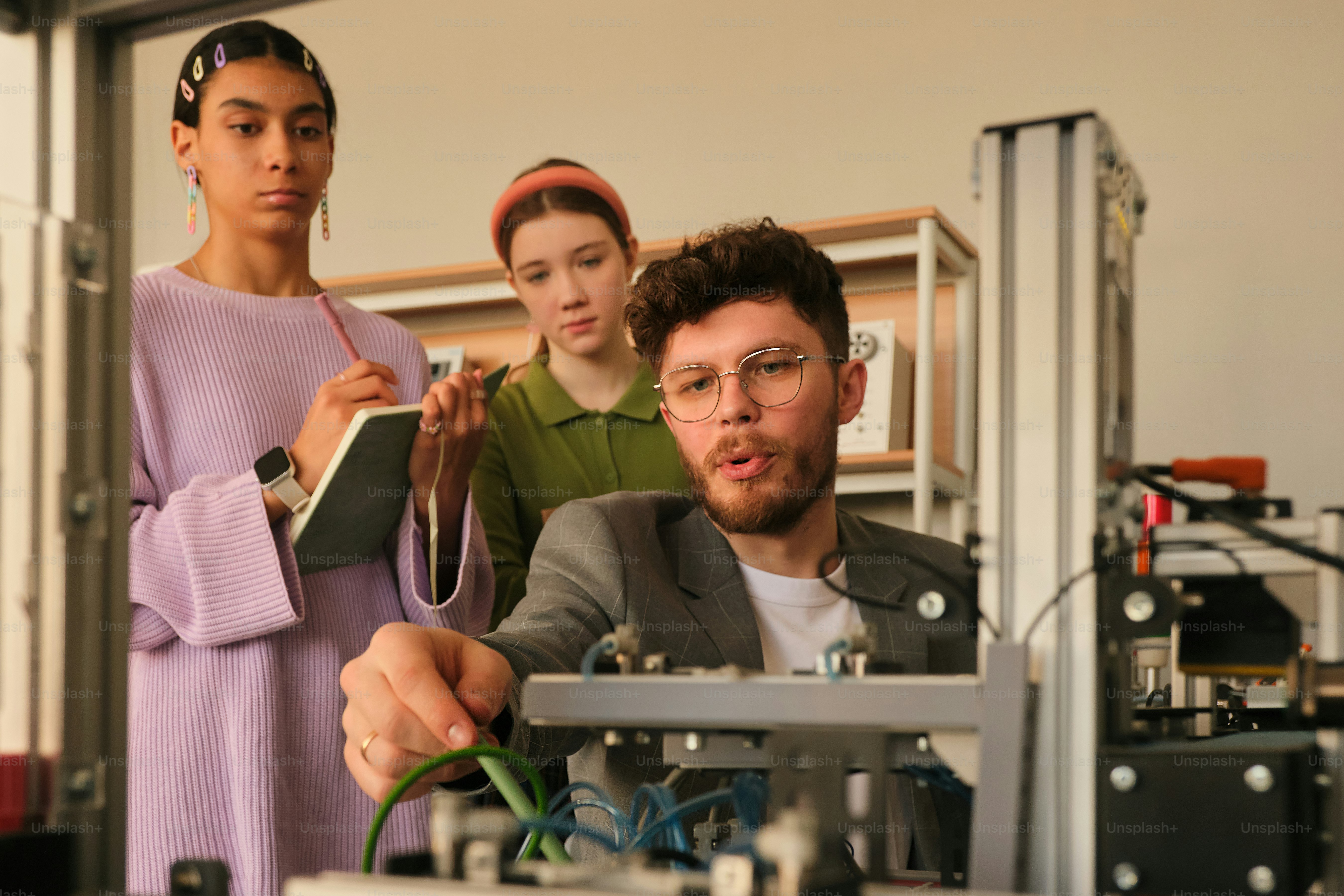 Students are studying a machine with their professor. photo ...