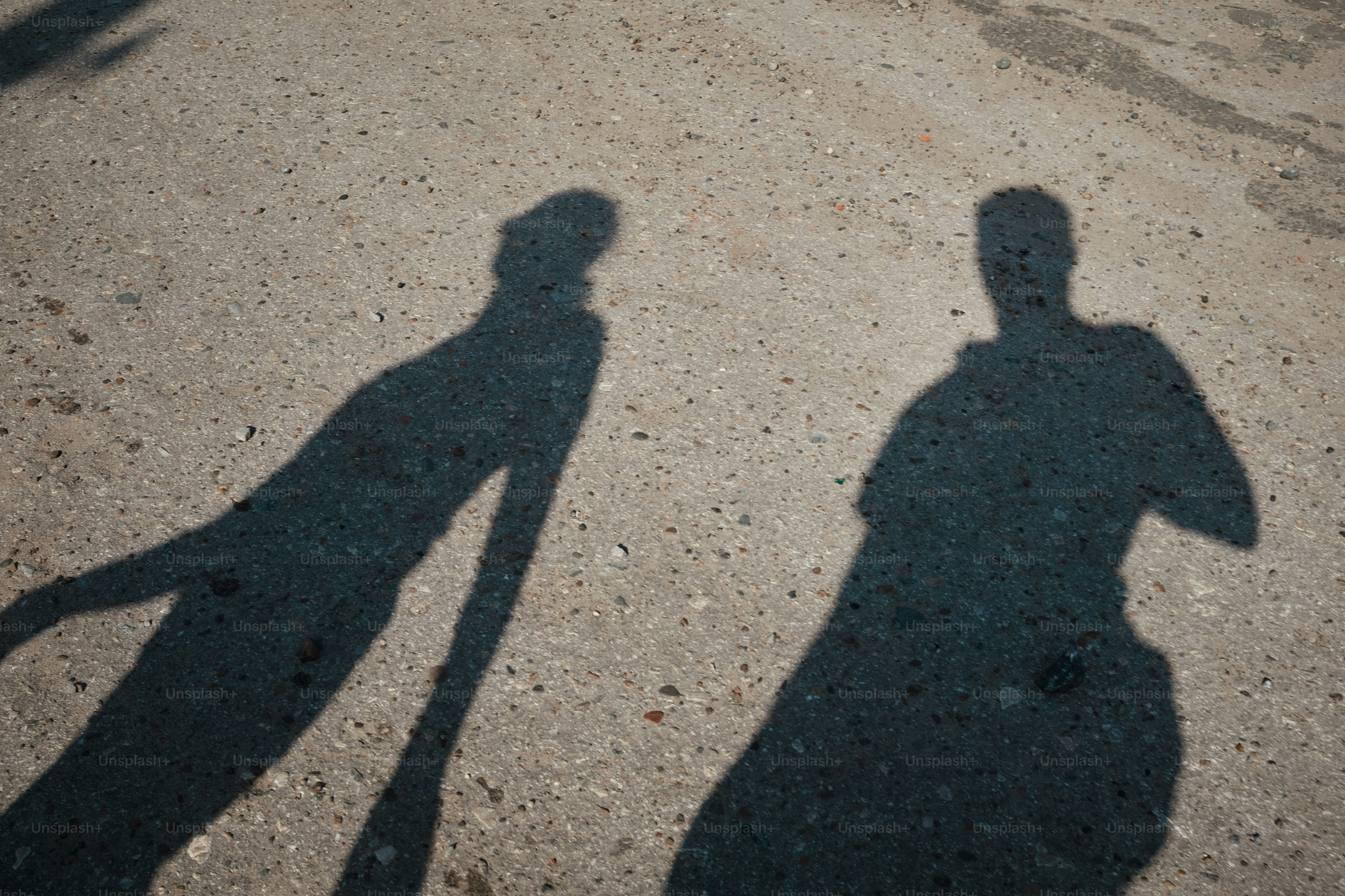 Two people's shadows are cast on a surface. photo – Photography Image ...