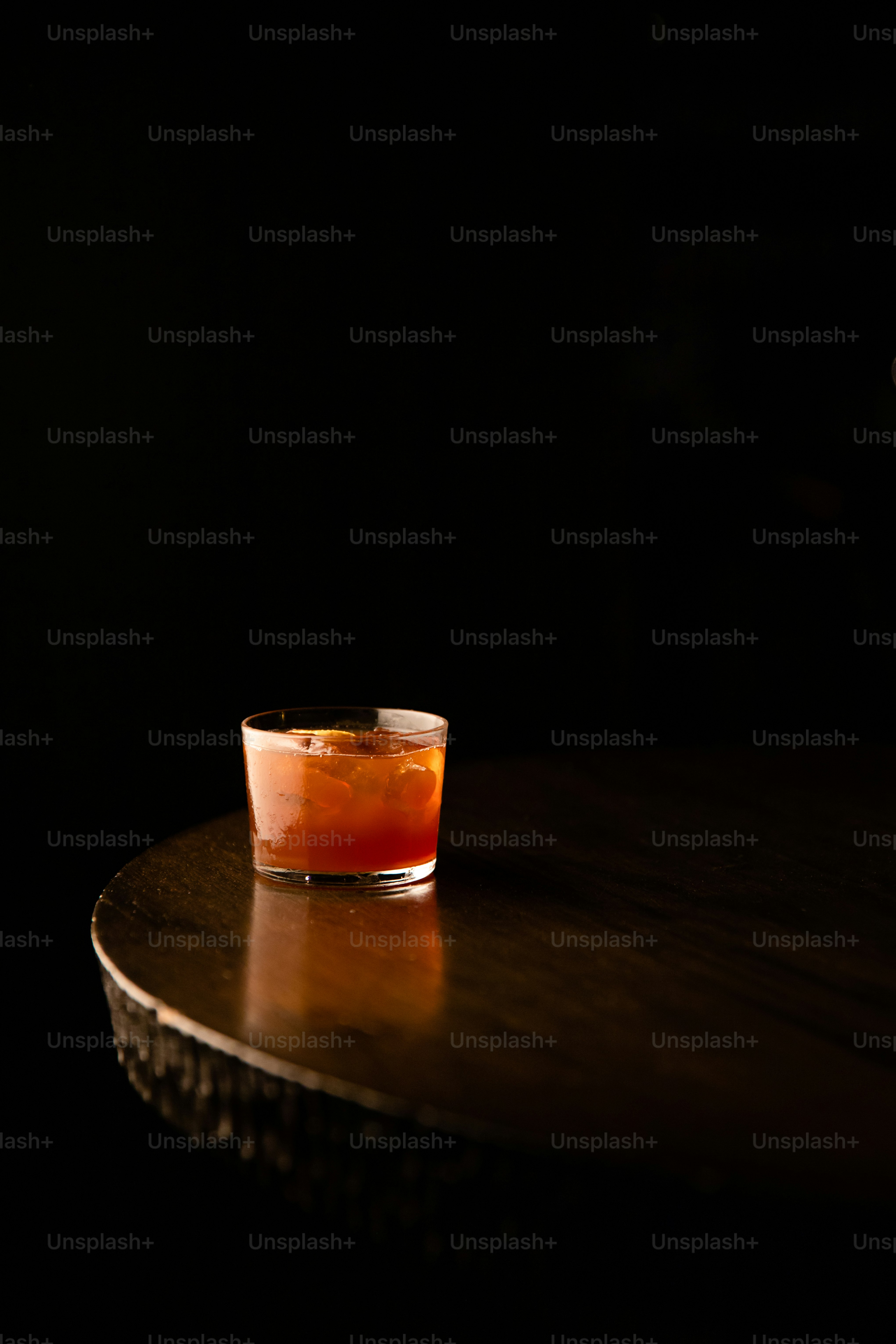 A cocktail sits on a dark, round table. photo – Dark background Image on Unsplash