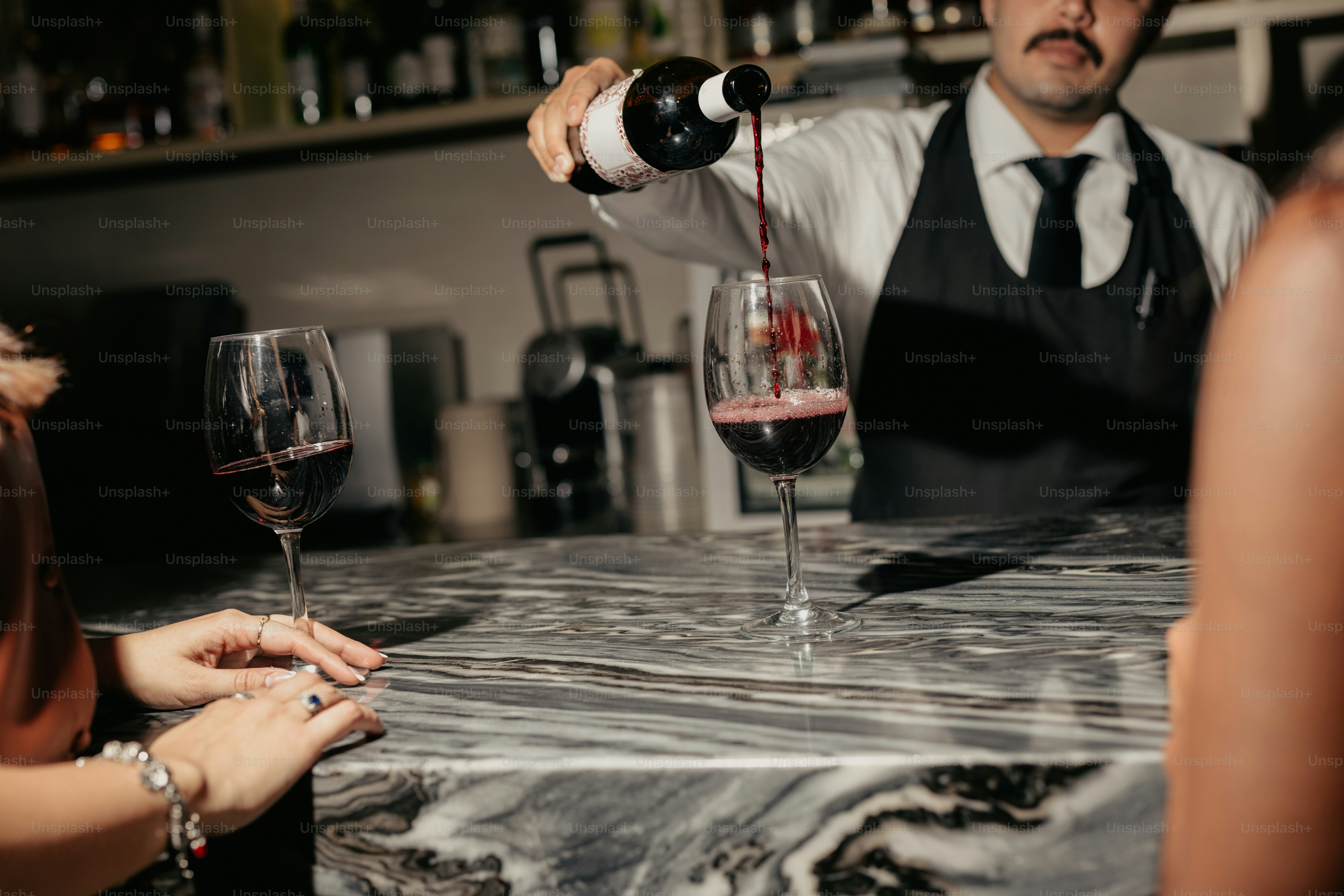 A bartender pours wine into a glass. photo – Bar Image on Unsplash