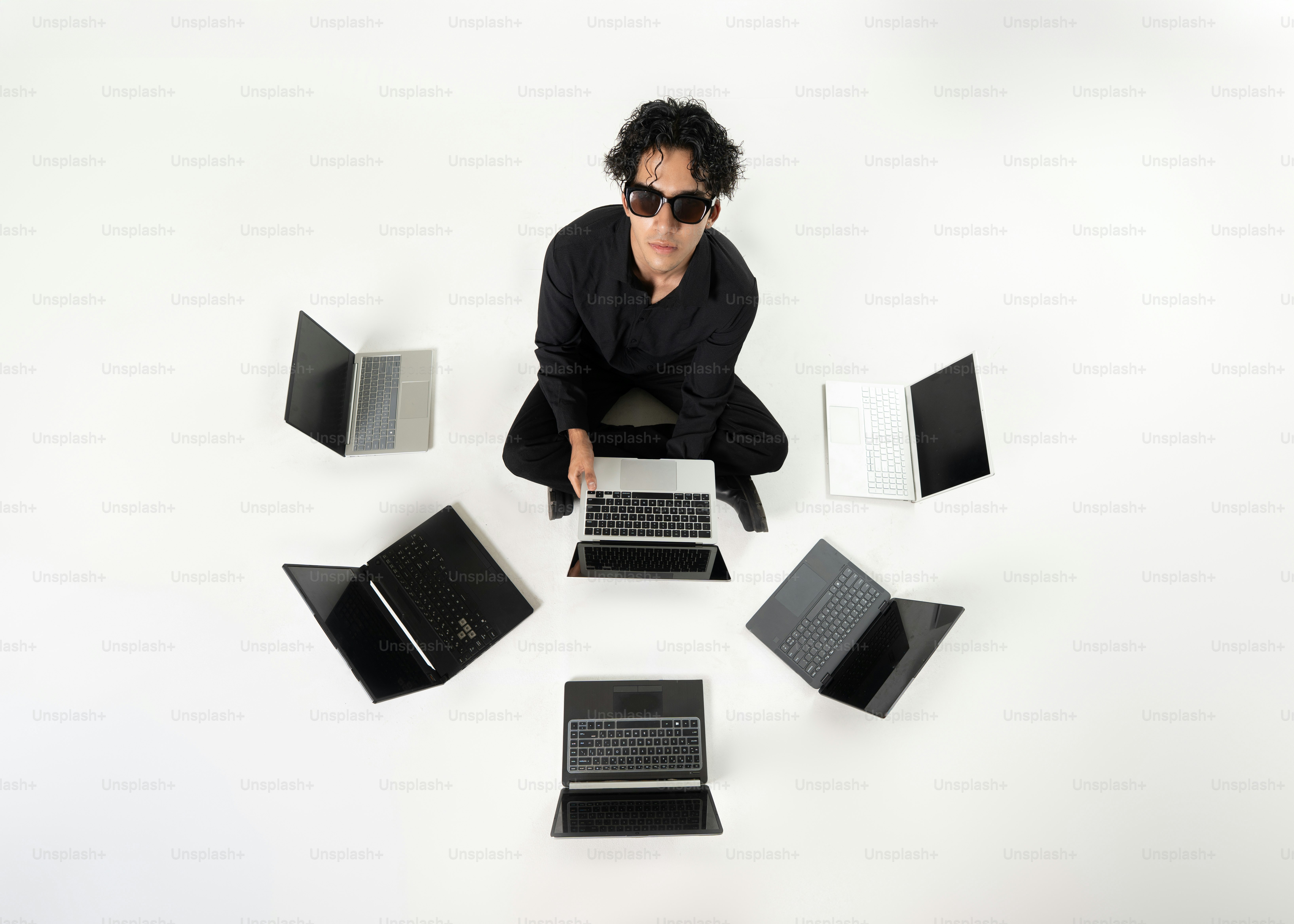 A person surrounded by open laptops. photo – Technology Image on Unsplash