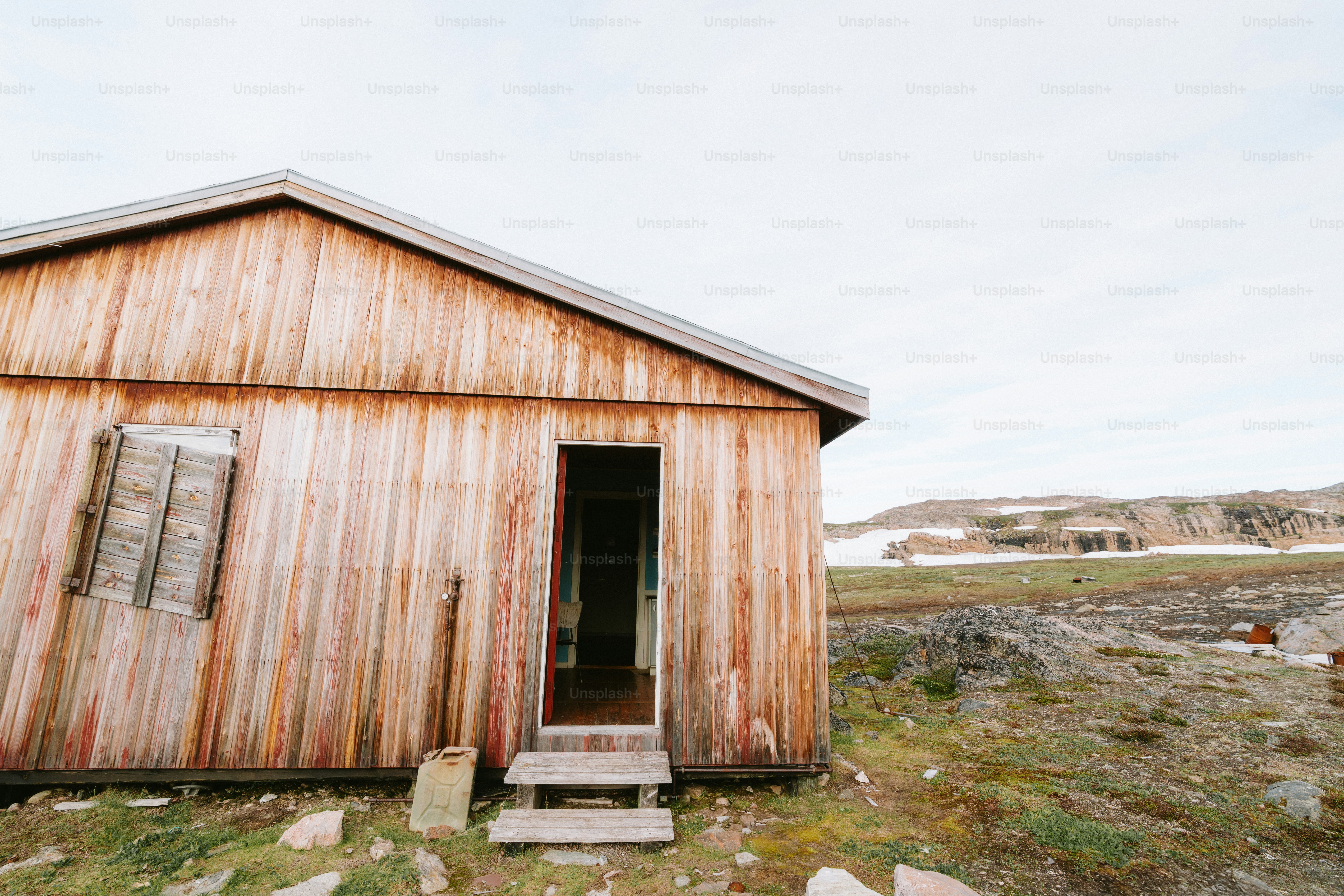 A wooden cabin stands in a barren landscape. photo – Building Image on ...