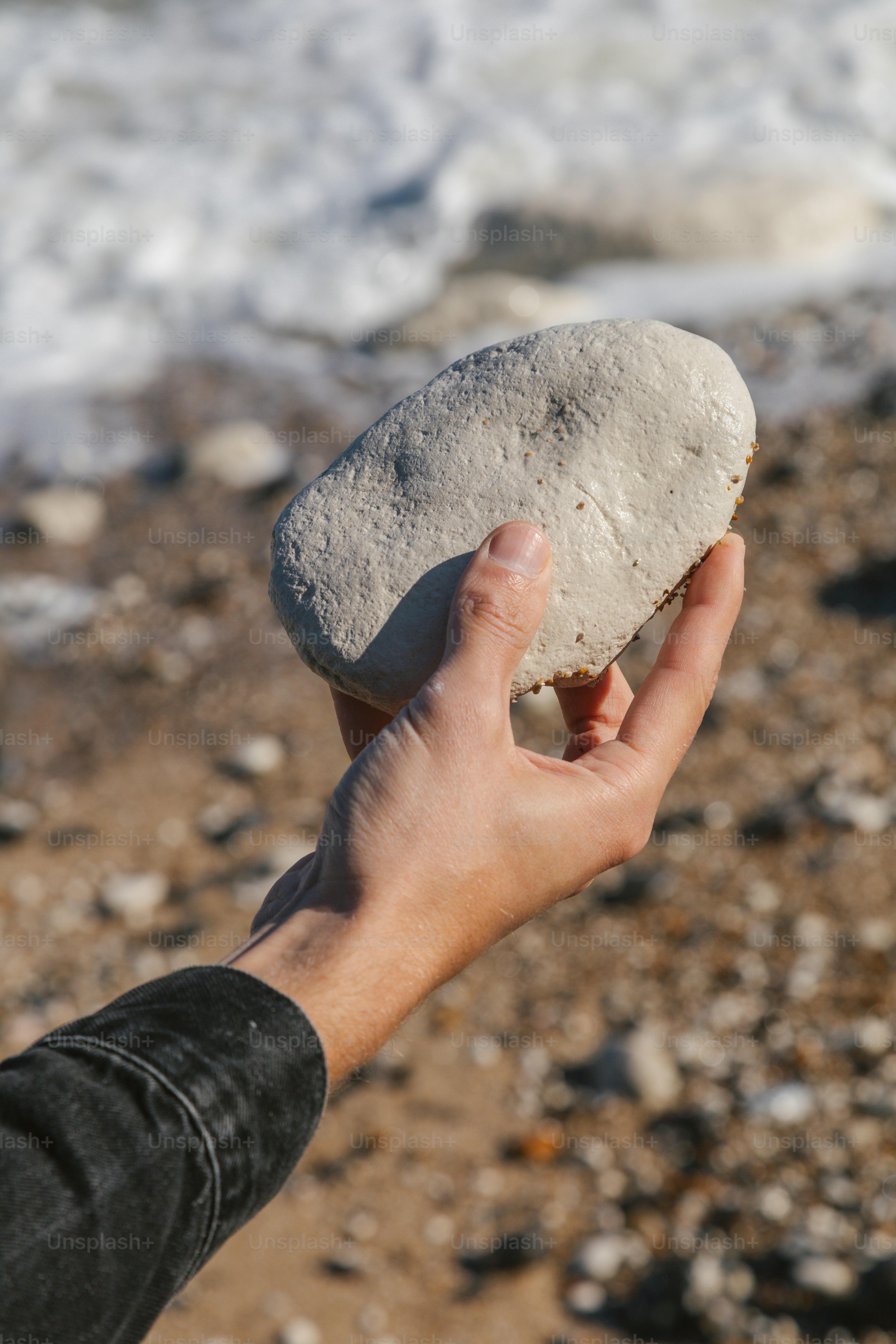 A hand holds a light-colored rock. photo – Texture Image on Unsplash