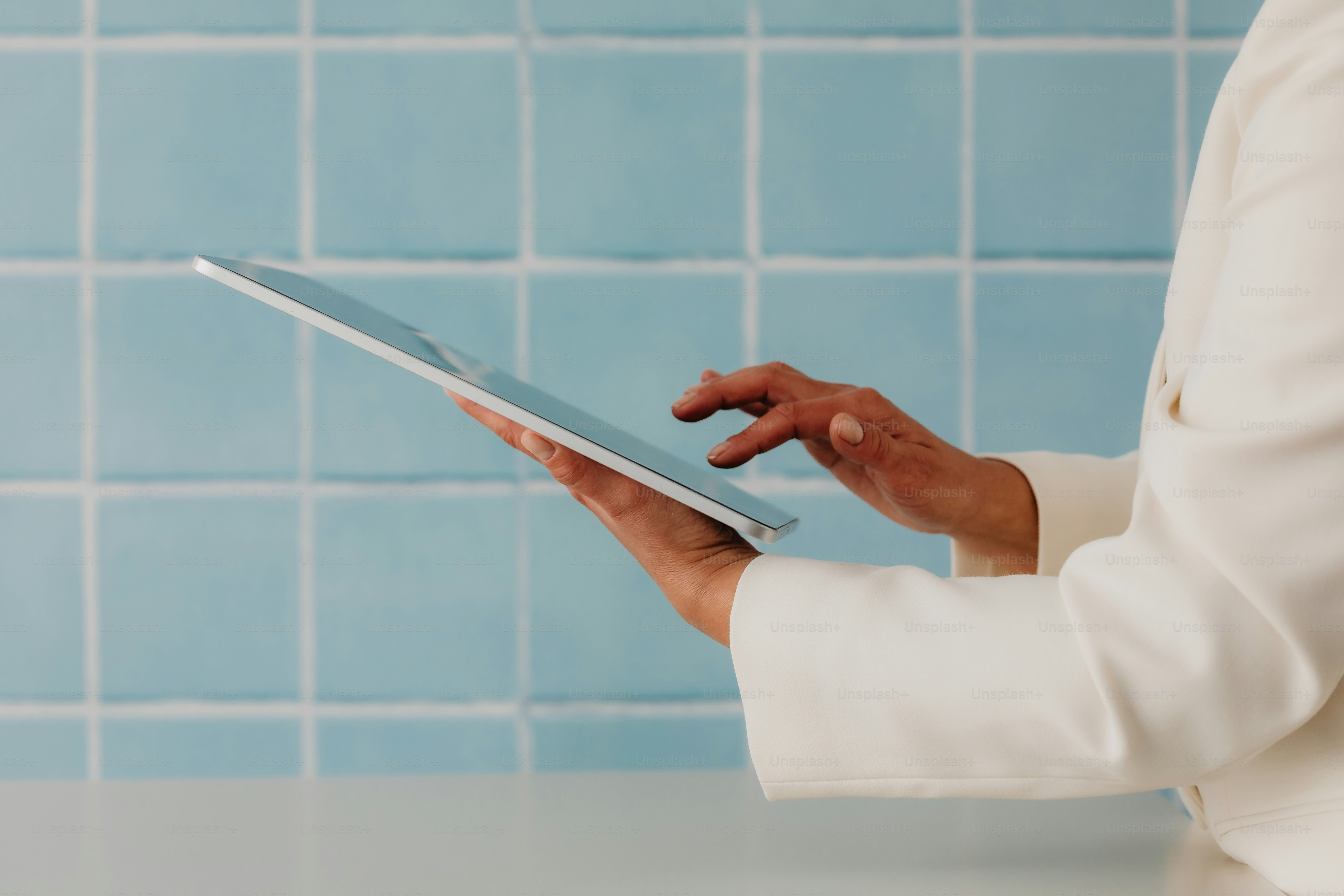 Eine Person verwendet ein Tablet vor blauem Hintergrund. Foto – Bild ...