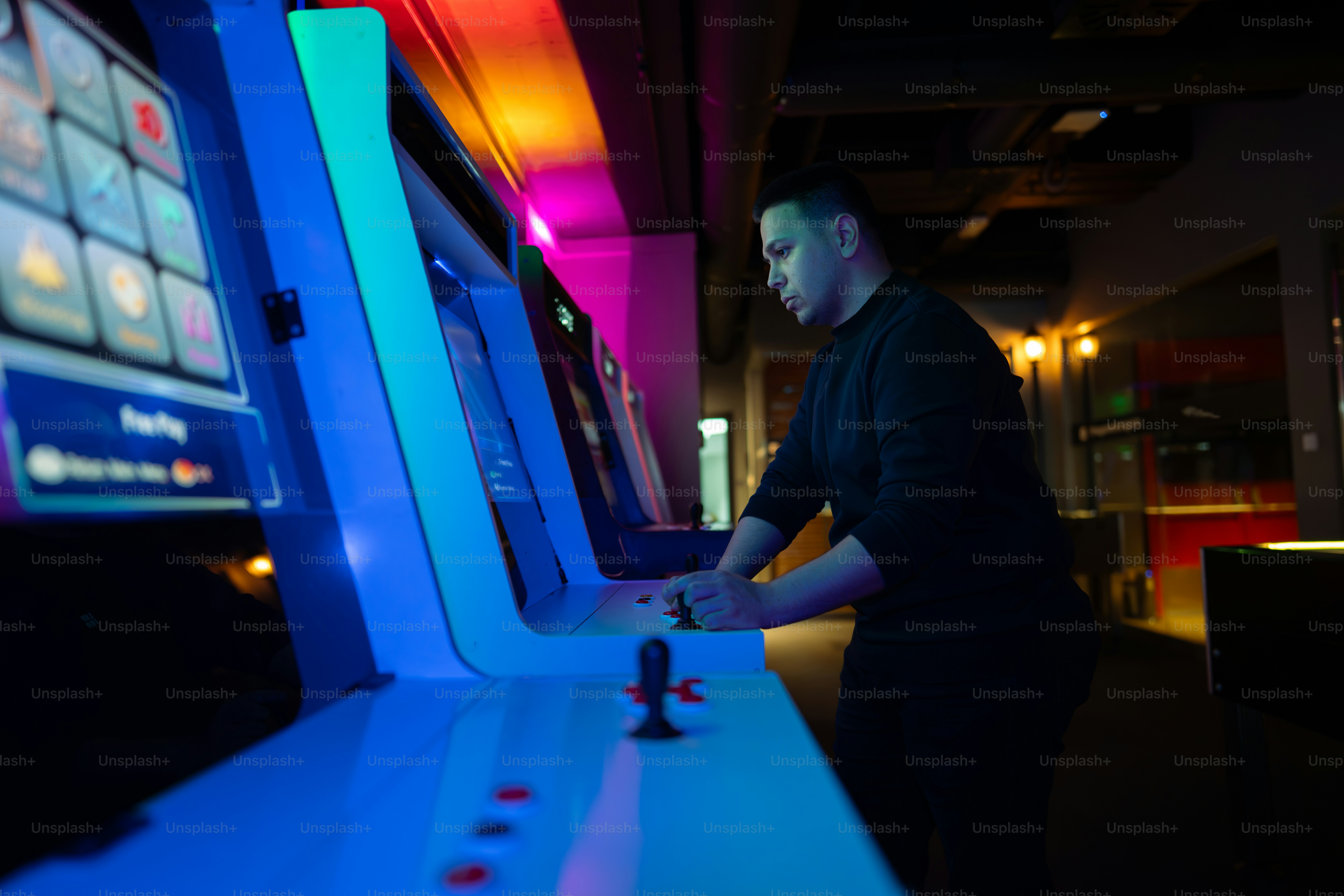 Man plays a game at a brightly lit arcade. photo – Gaming Image on Unsplash