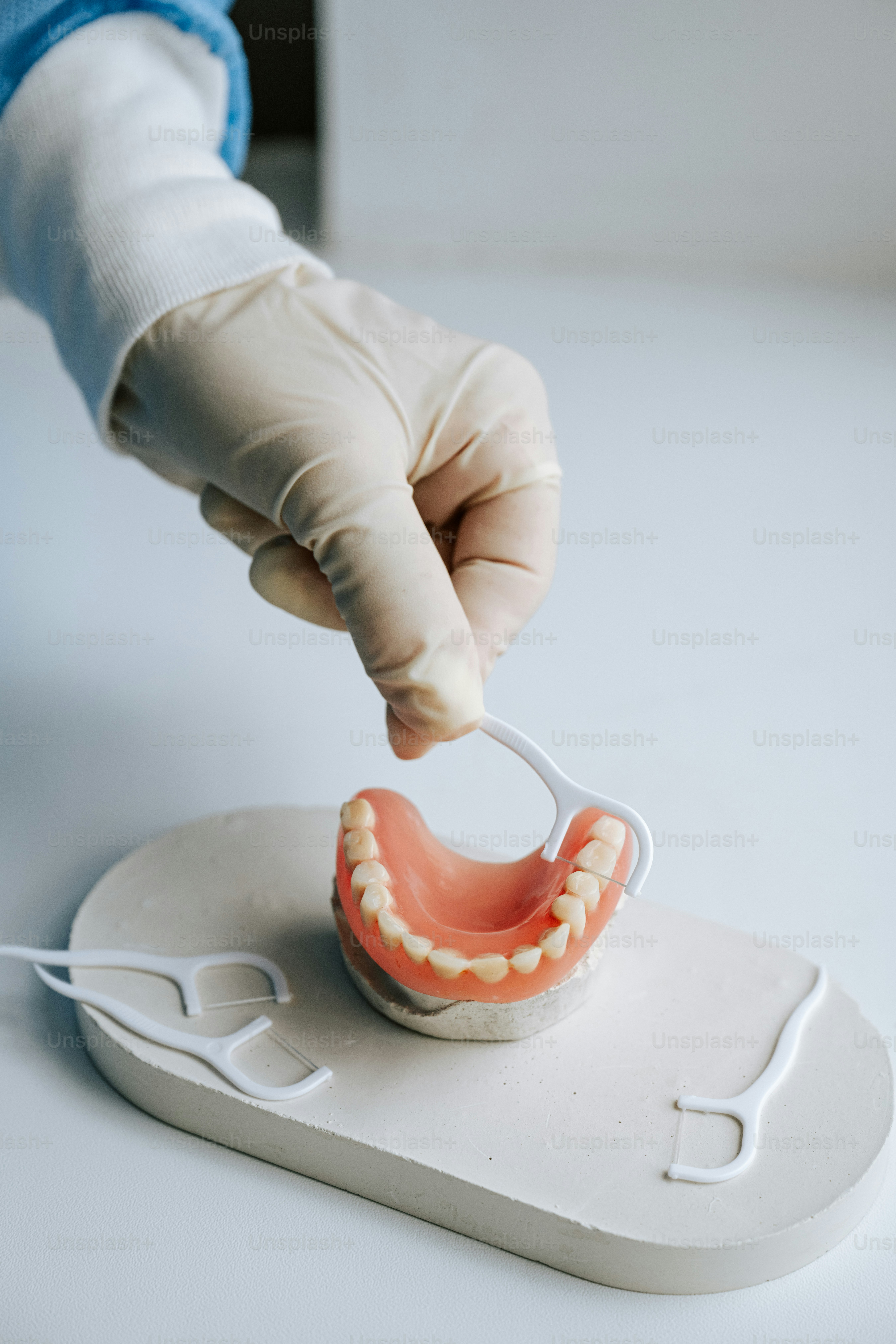 A dentist is using floss on a denture. photo – Dental Image on Unsplash